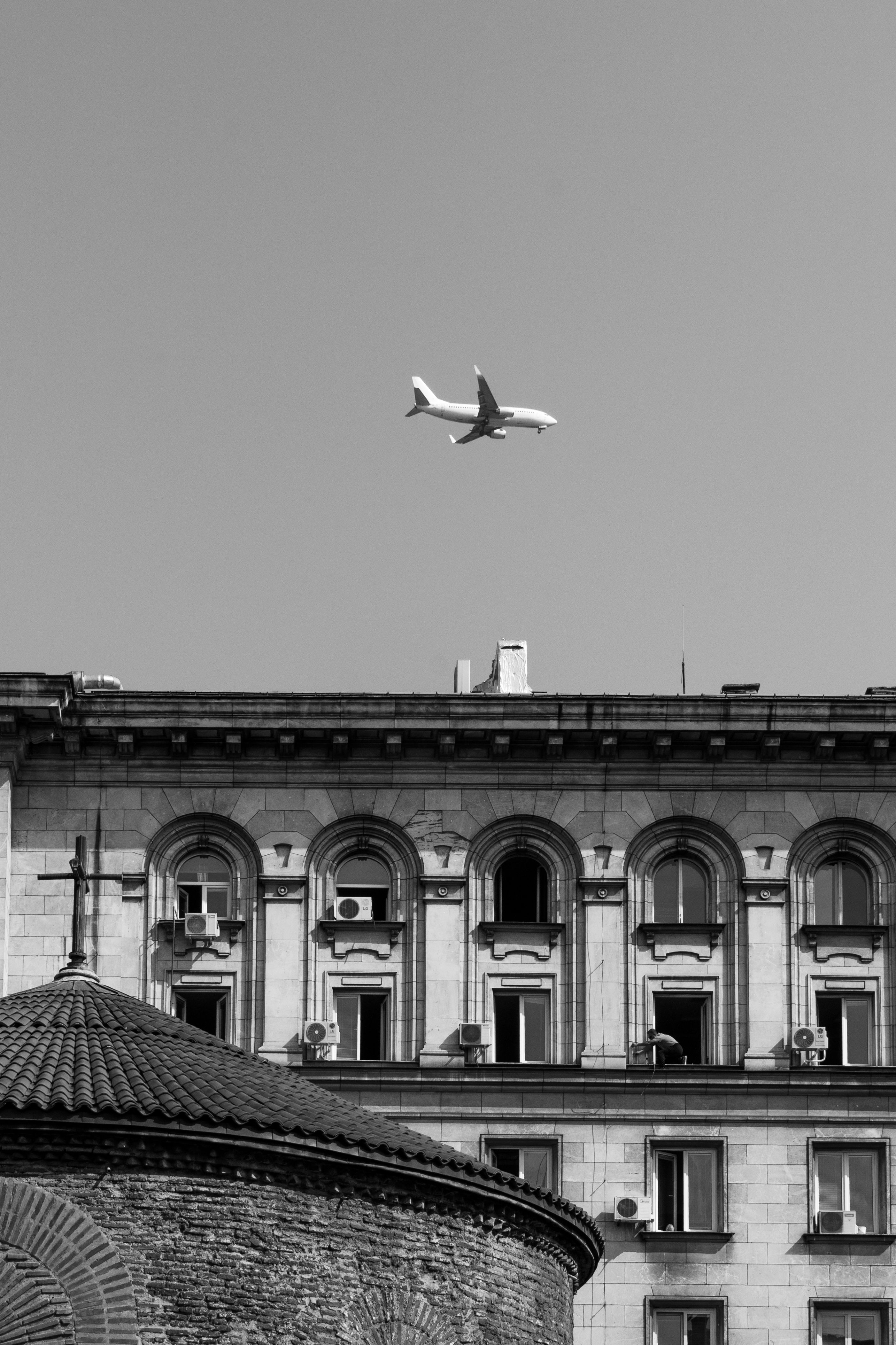 Airplane Flying Over Historic Building in Monochrome · Free Stock Photo