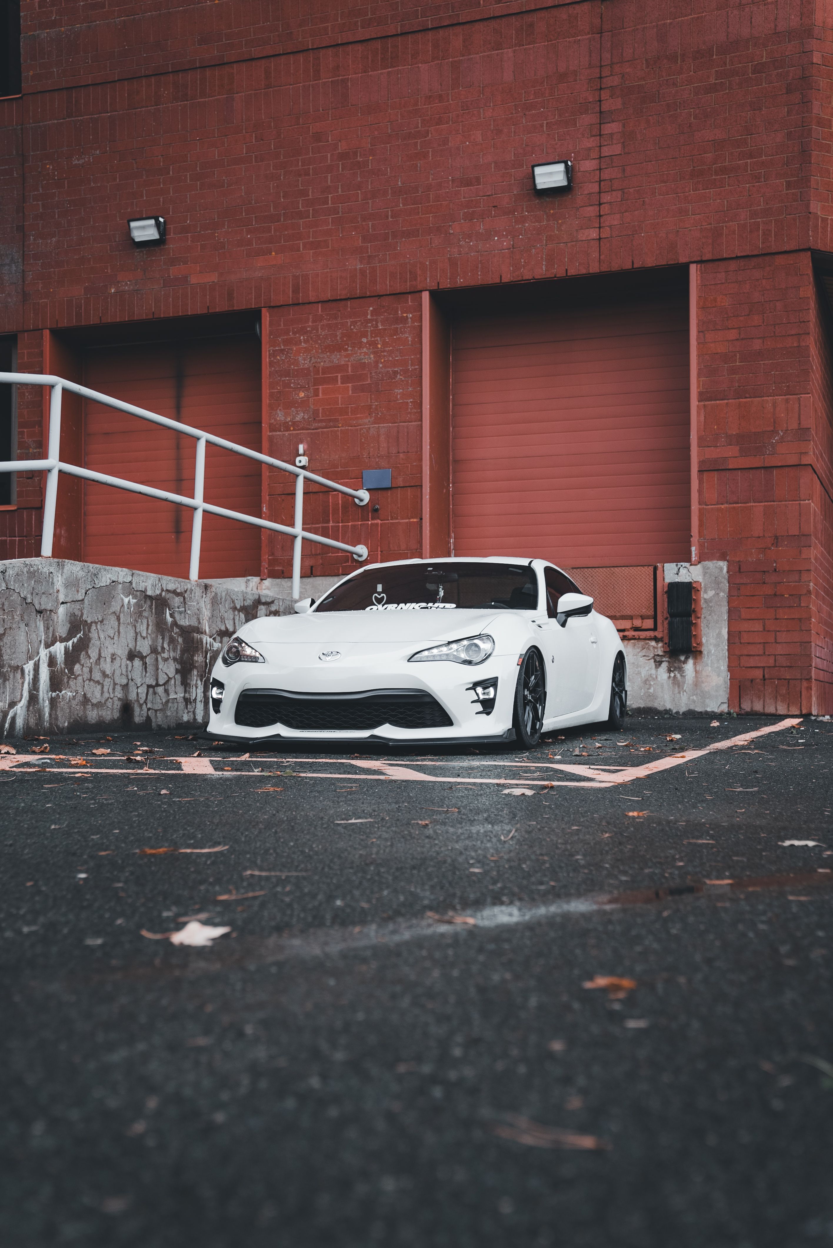 White Sports Car Parked Against Brick Wall · Free Stock Photo