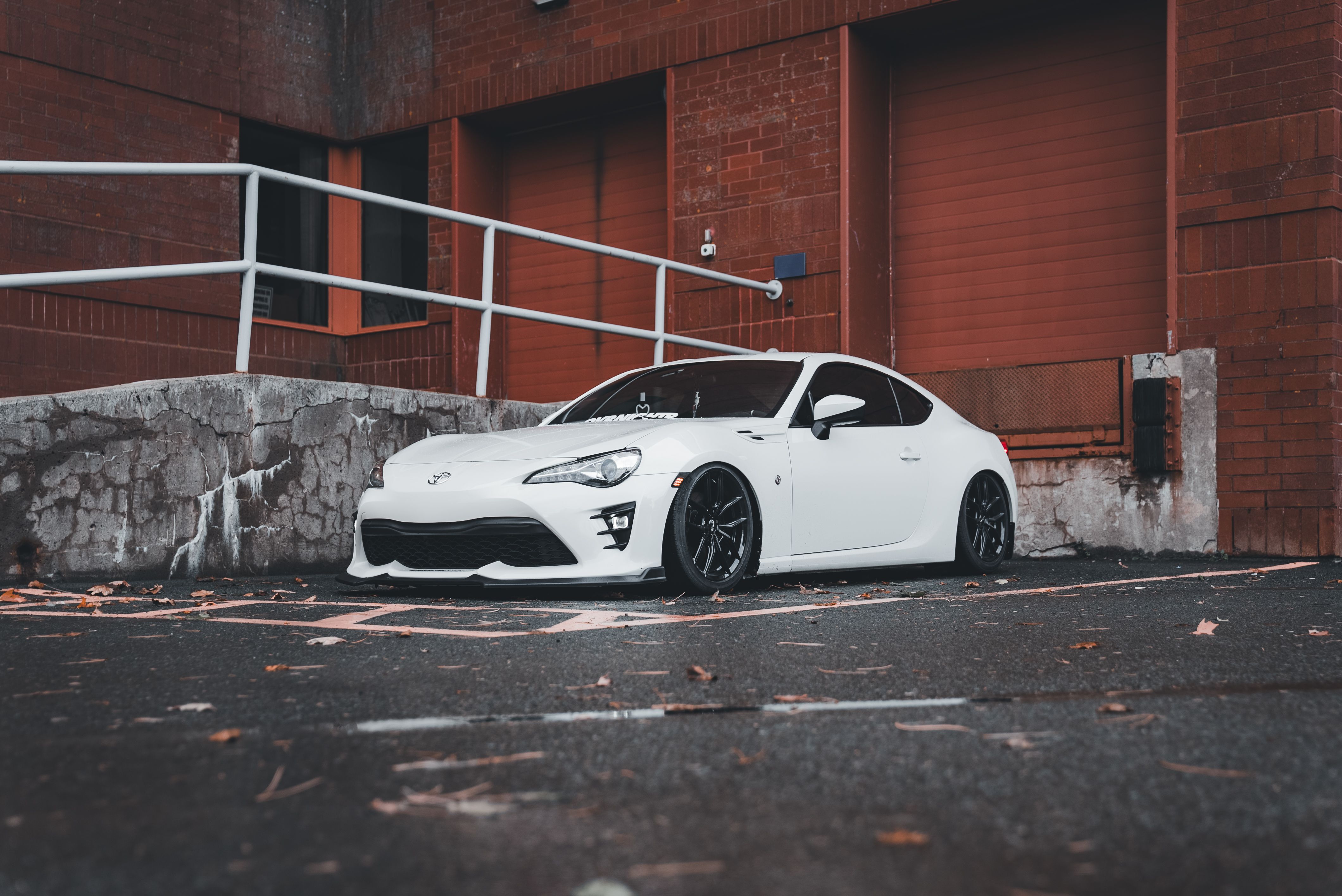 White Sports Car Parked by Brick Wall Urban Setting · Free Stock Photo