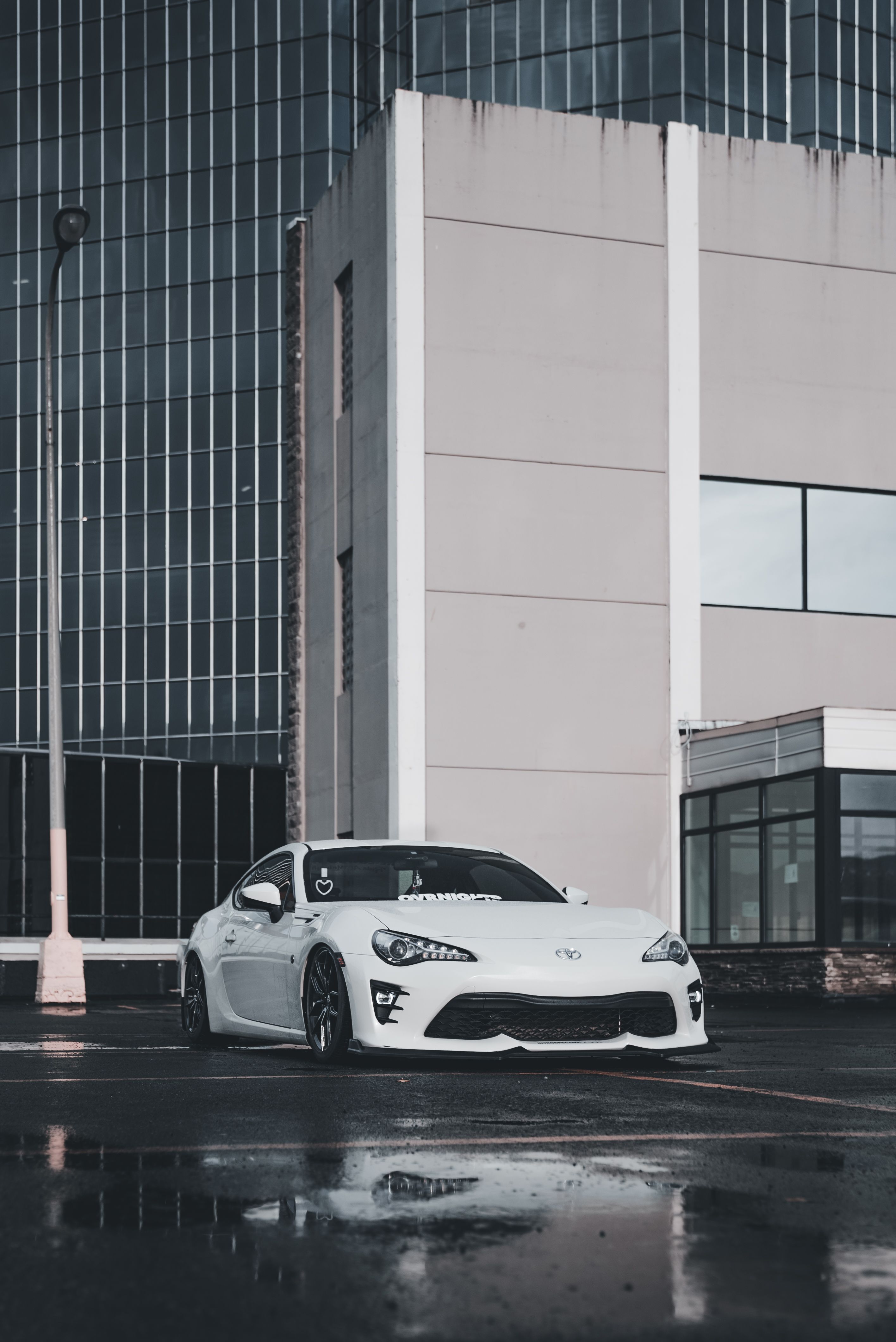 Sleek White Car in Urban Rainy Setting · Free Stock Photo