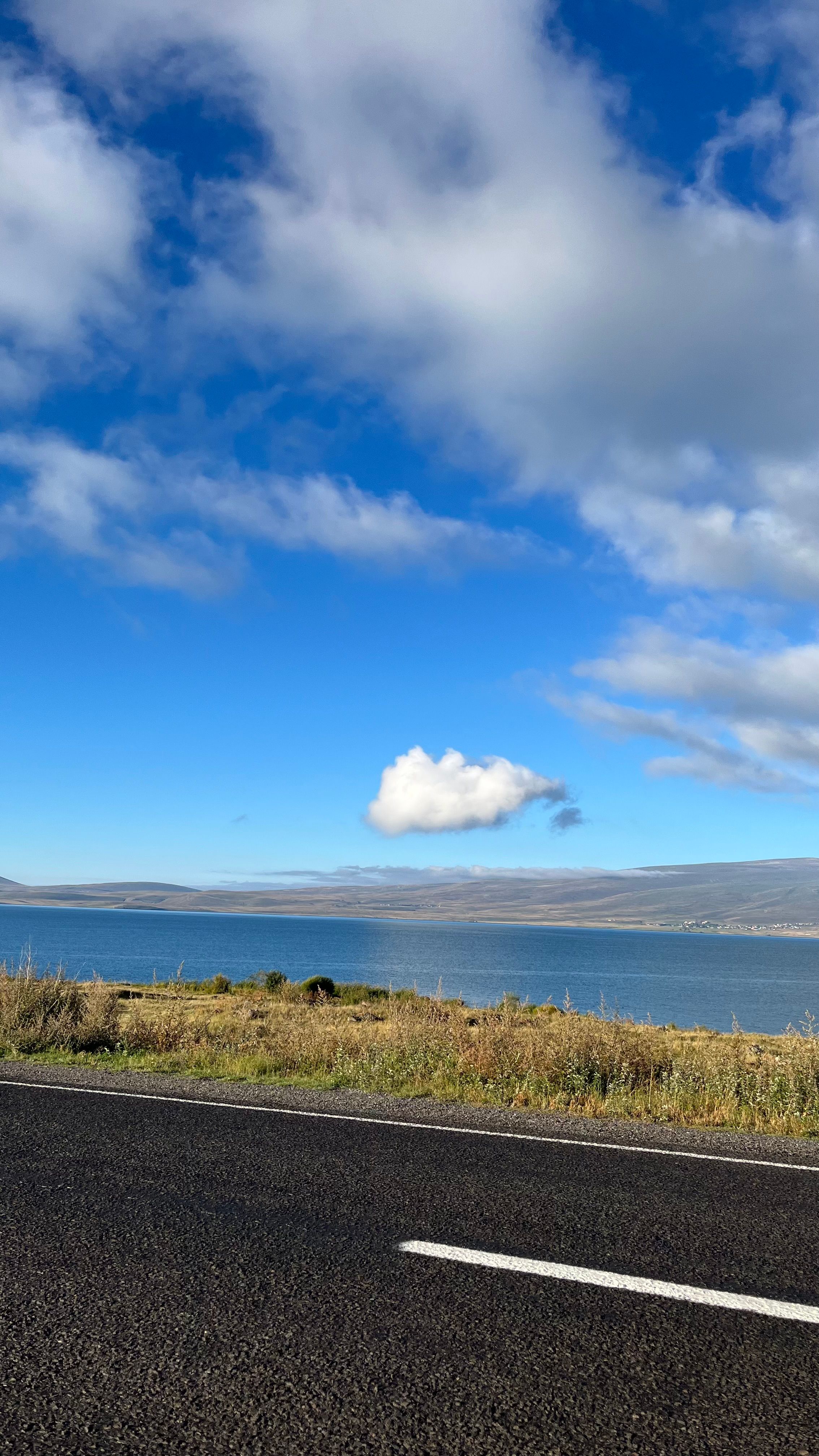 Scenic Lakeside Road Under Blue Sky · Free Stock Photo