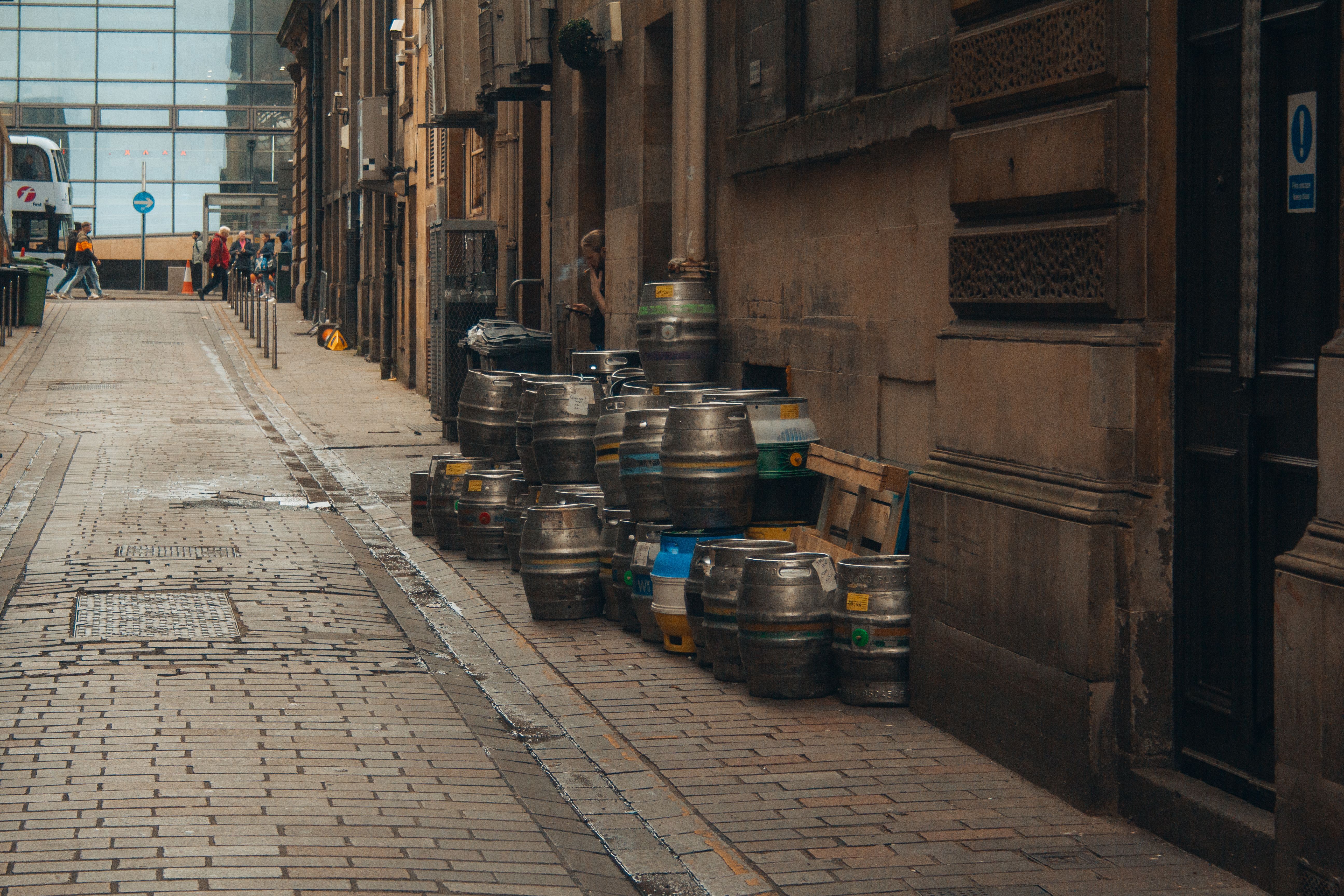 Urban Alley with Metal Beer Kegs and Cobblestones · Free Stock Photo