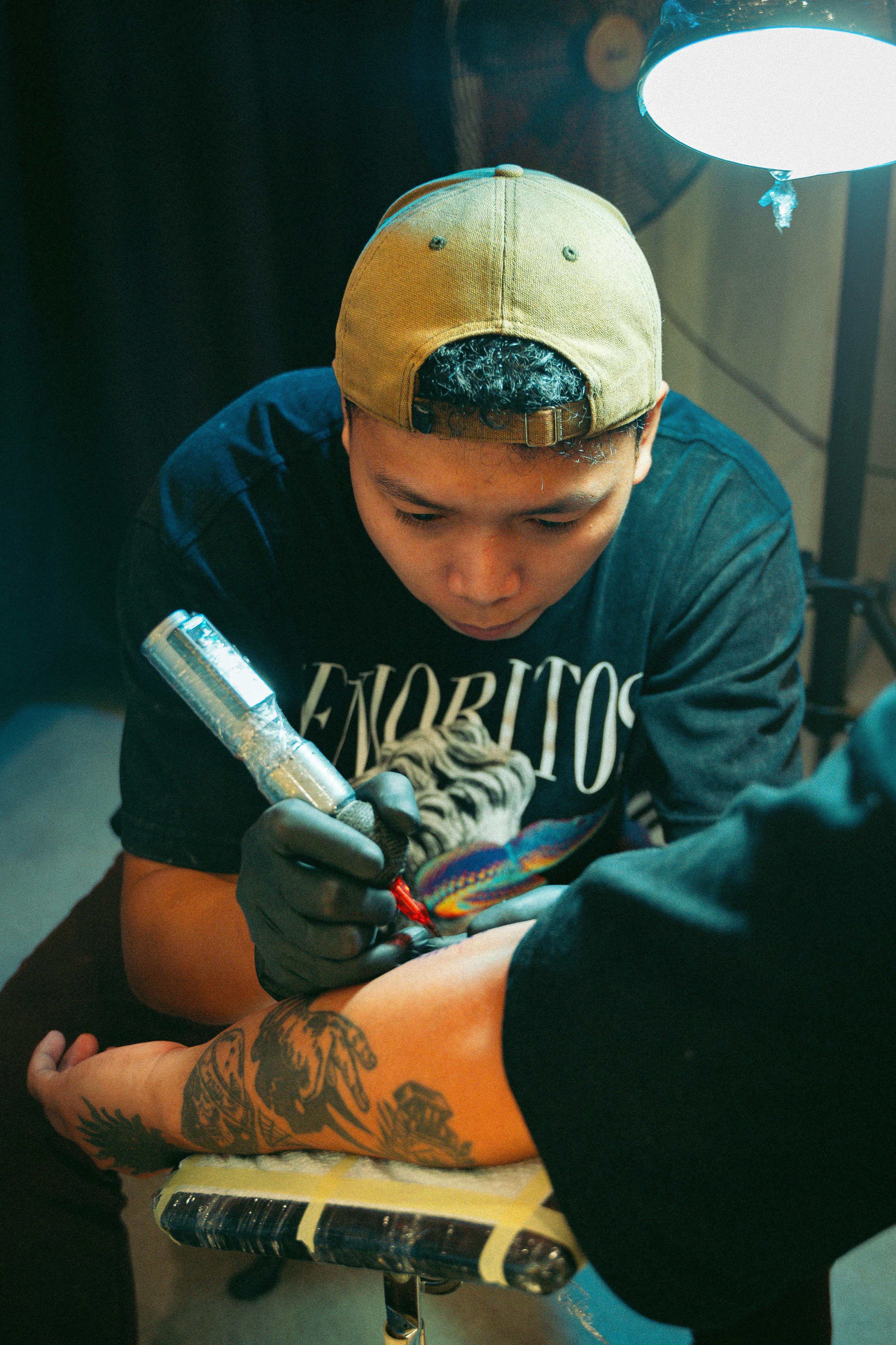 Tattoo Artist Skillfully Inking Client's Arm · Free Stock Photo
