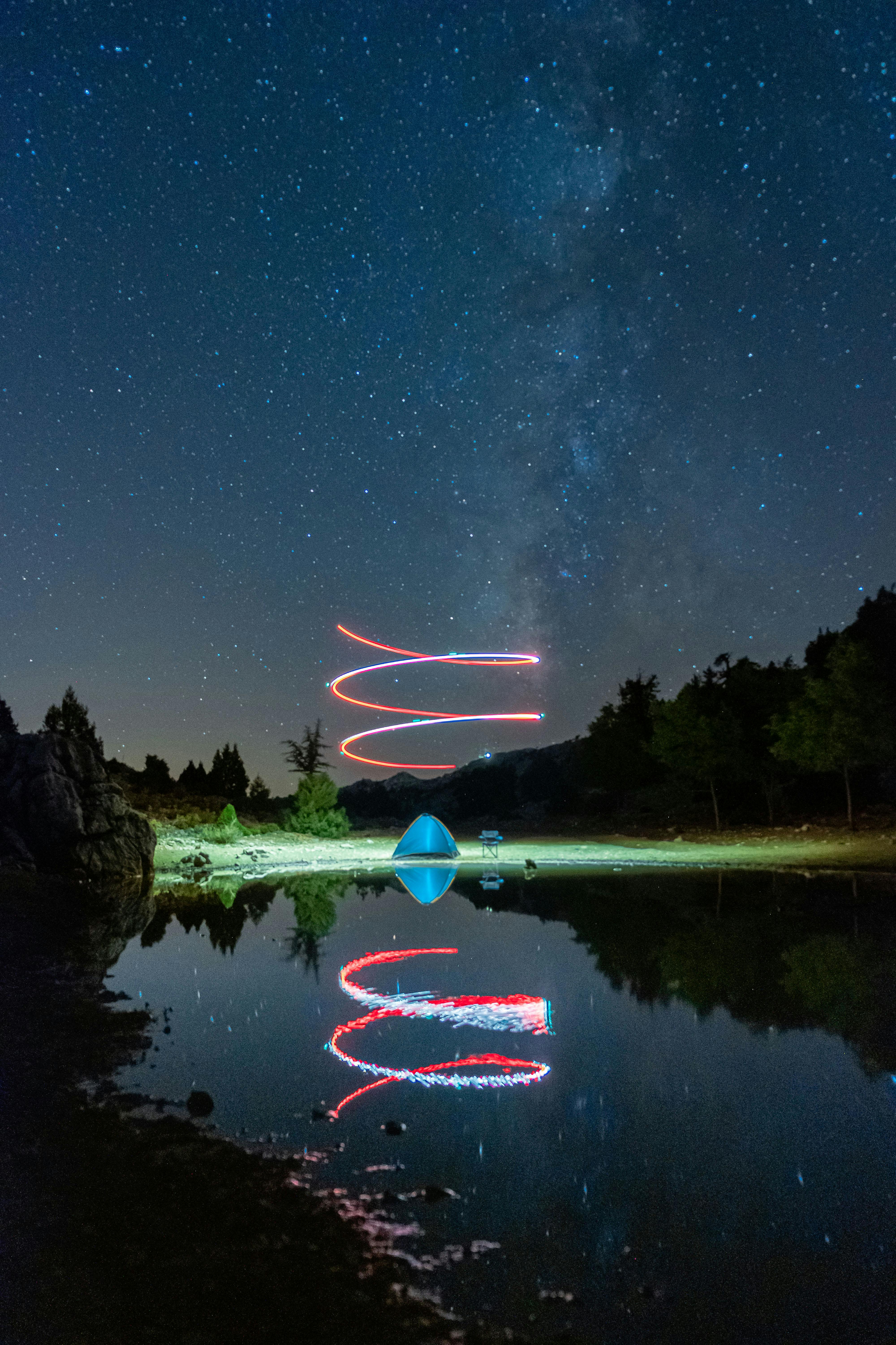 Starry Night Sky with Light Trails and Tent Reflection · Free Stock Photo
