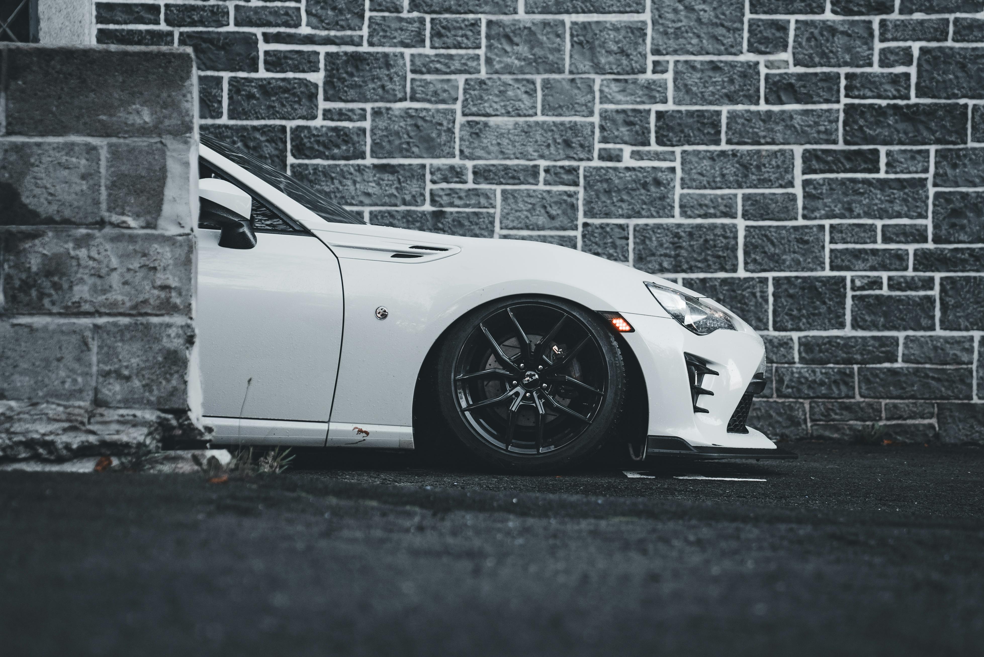 Sleek White Sports Car by Stone Wall · Free Stock Photo