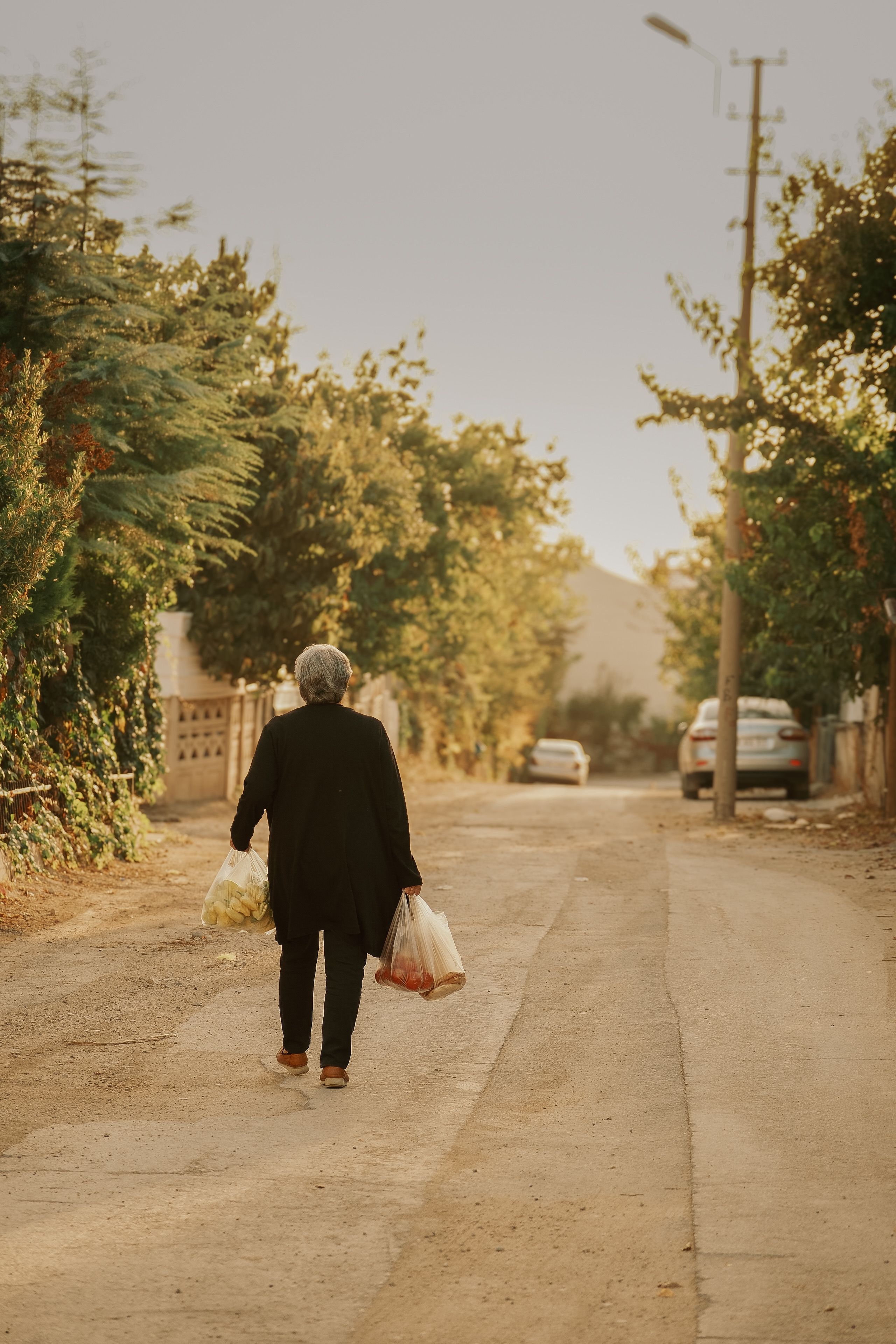 Elderly Person Walking Down Quiet Residential Street · Free Stock Photo