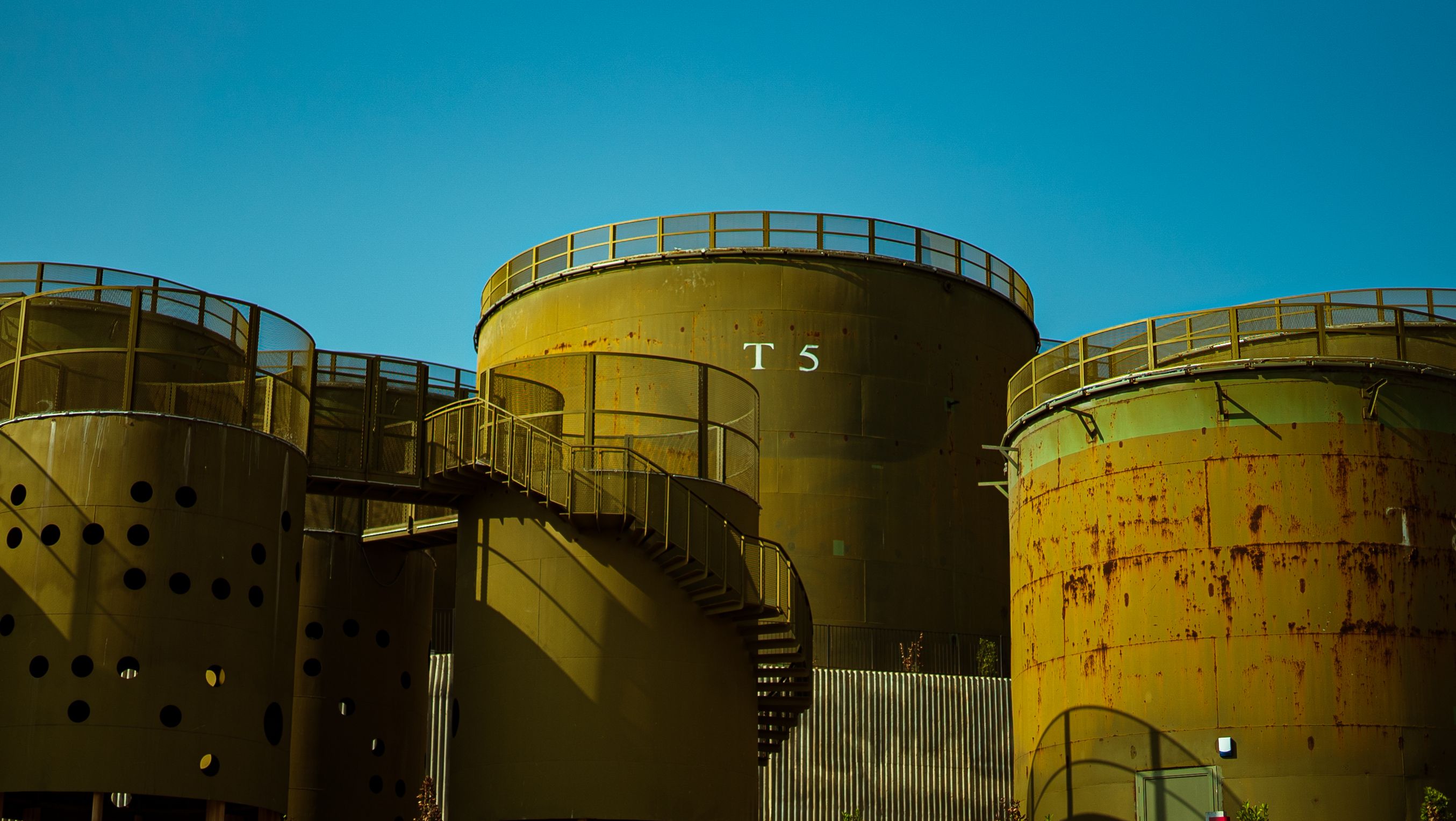 Industrial Storage Tanks Against Clear Blue Sky · Free Stock Photo