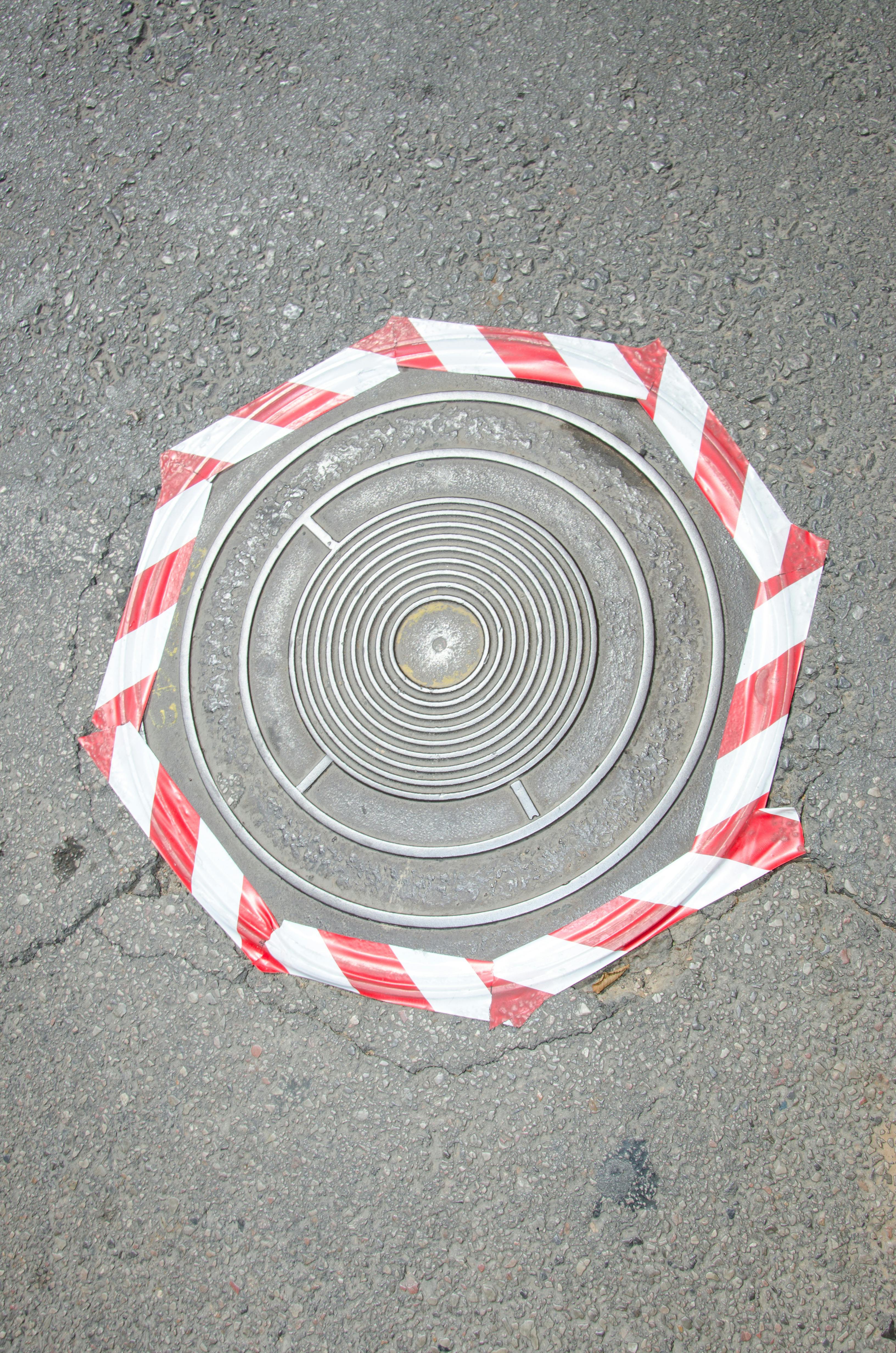 Road Maintenance: Manhole with Warning Tape · Free Stock Photo