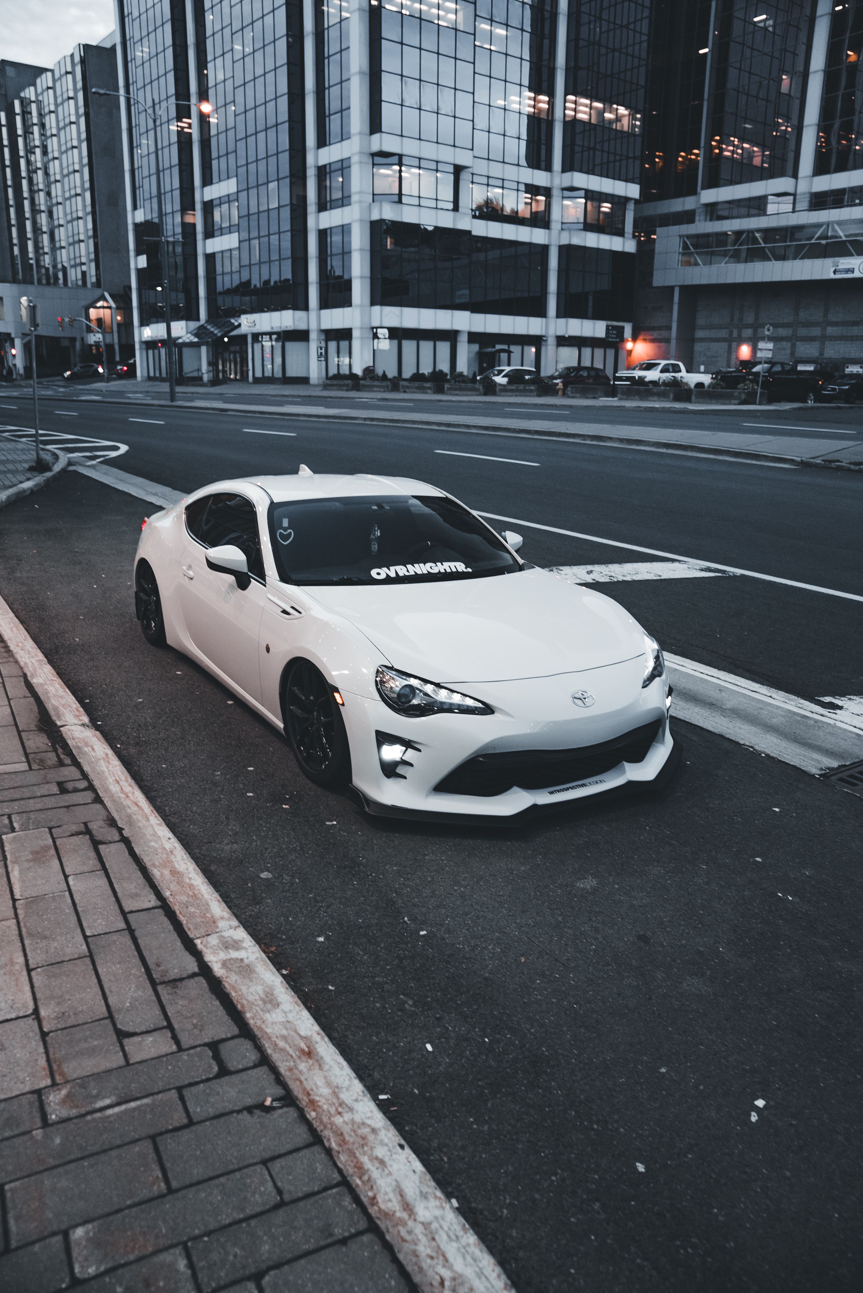 Sleek White Car on Urban Street at Dusk · Free Stock Photo