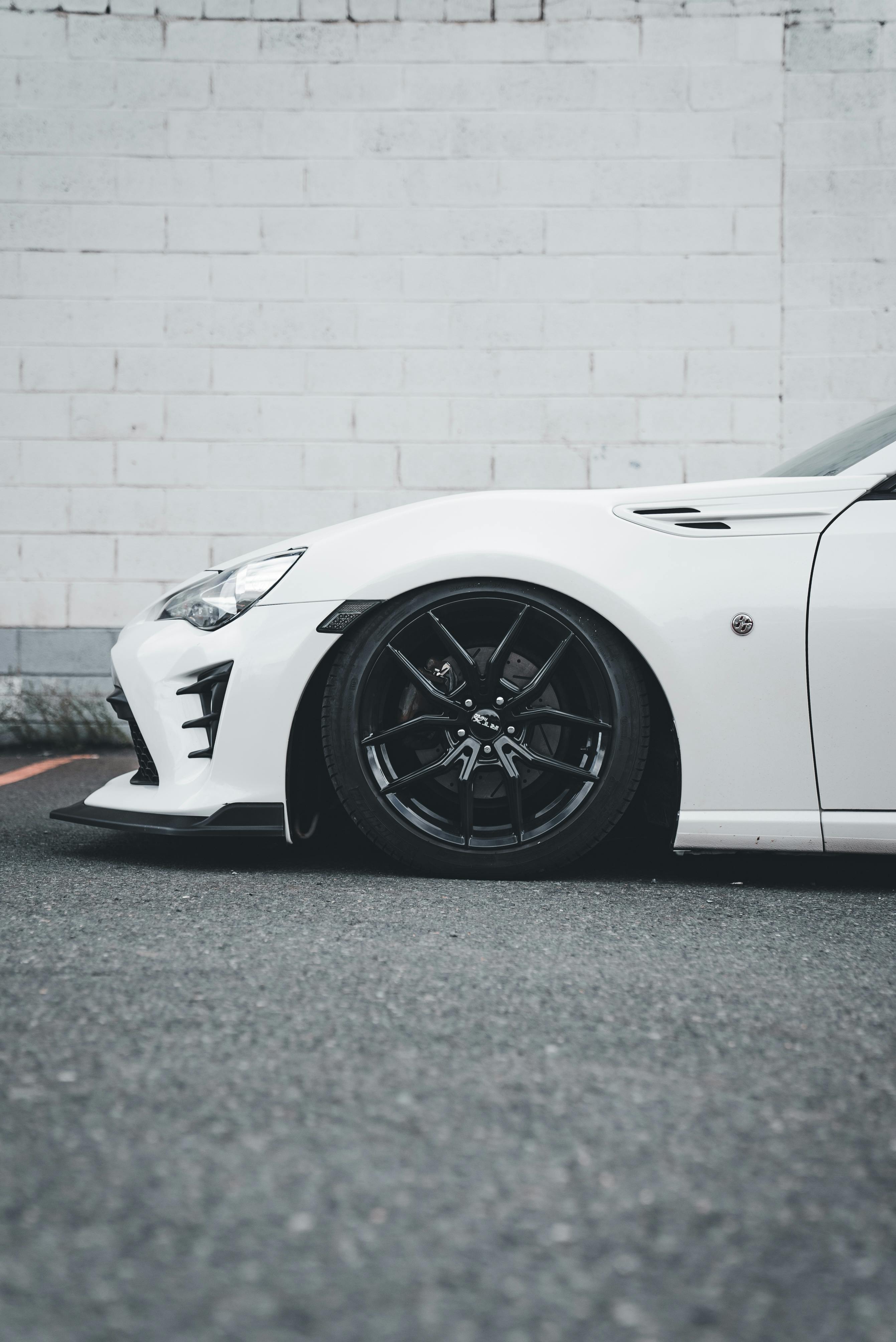 Sleek White Sports Car with Black Rims on Urban Street · Free Stock Photo