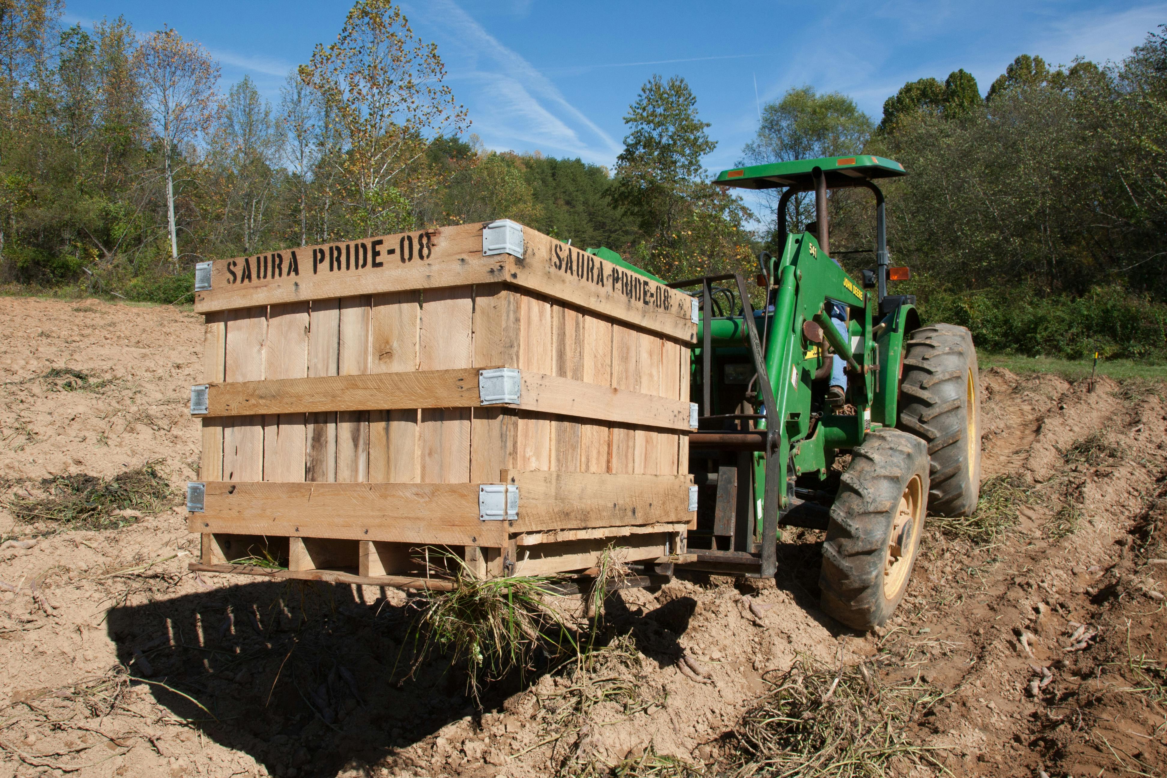 A Green Tractor Carrying a Wood Crate · Free Stock Photo