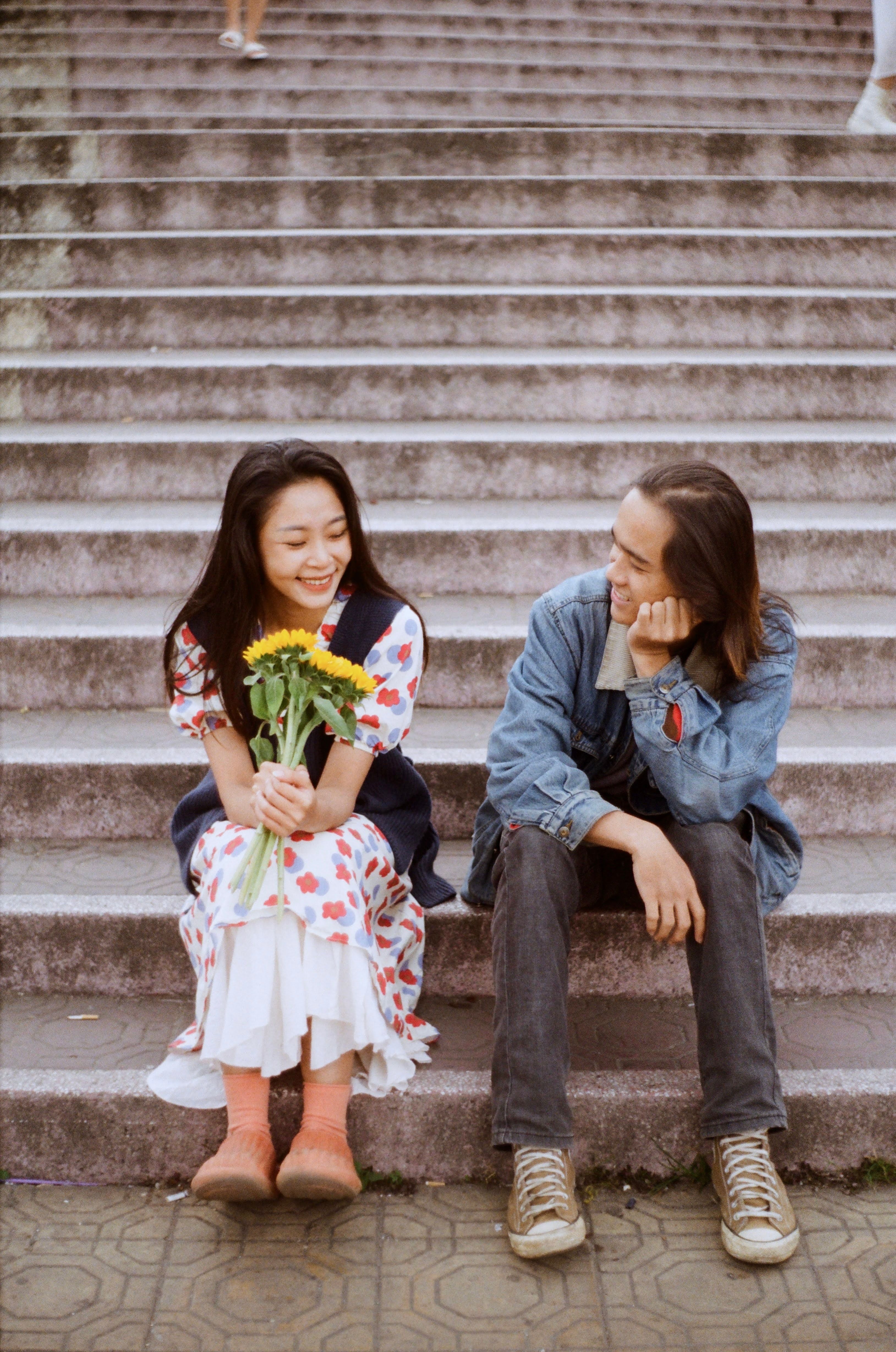 Young Couple Sitting on Outdoor Steps, Smiling · Free Stock Photo