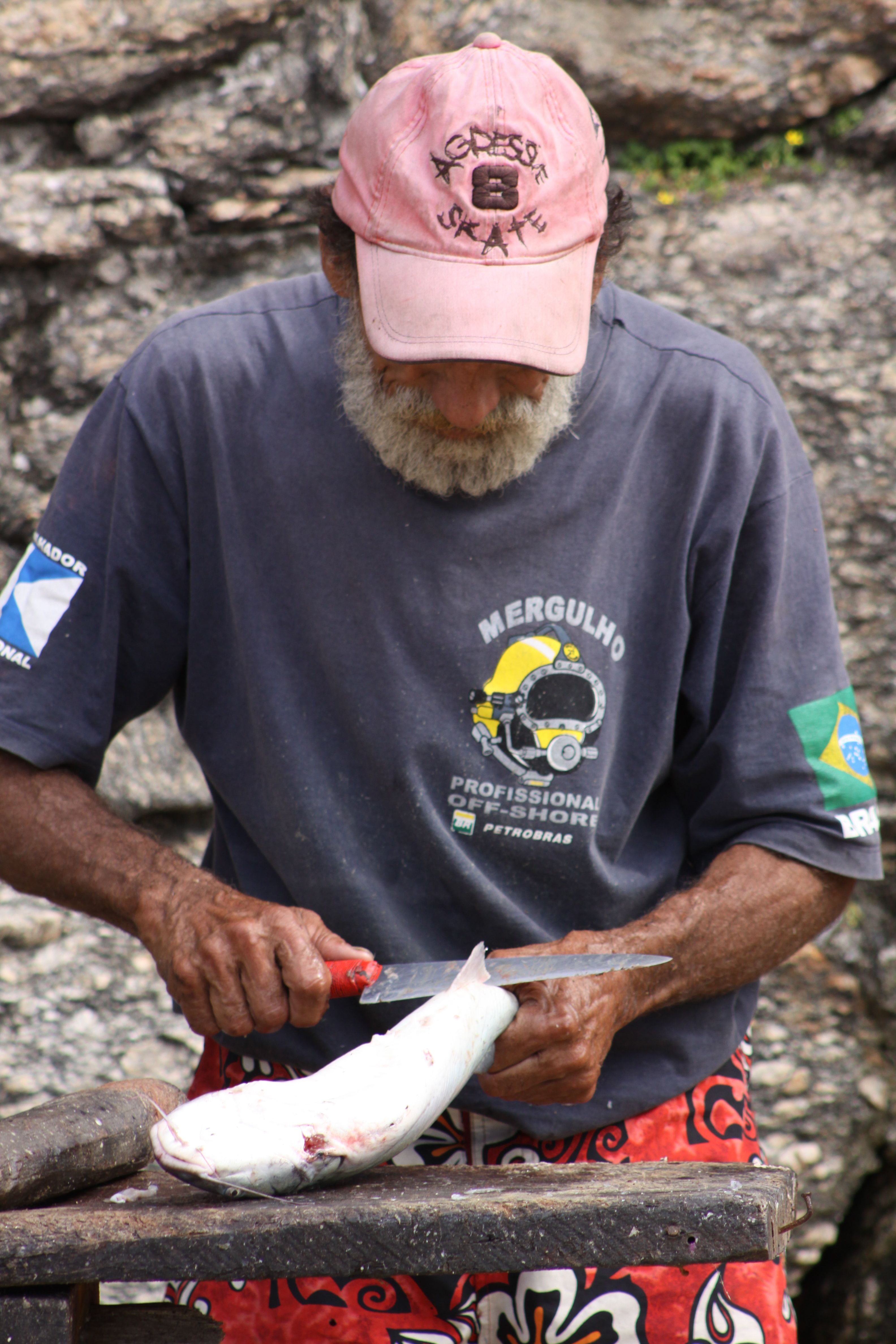 Elderly Man Filleting Fish Outdoors · Free Stock Photo
