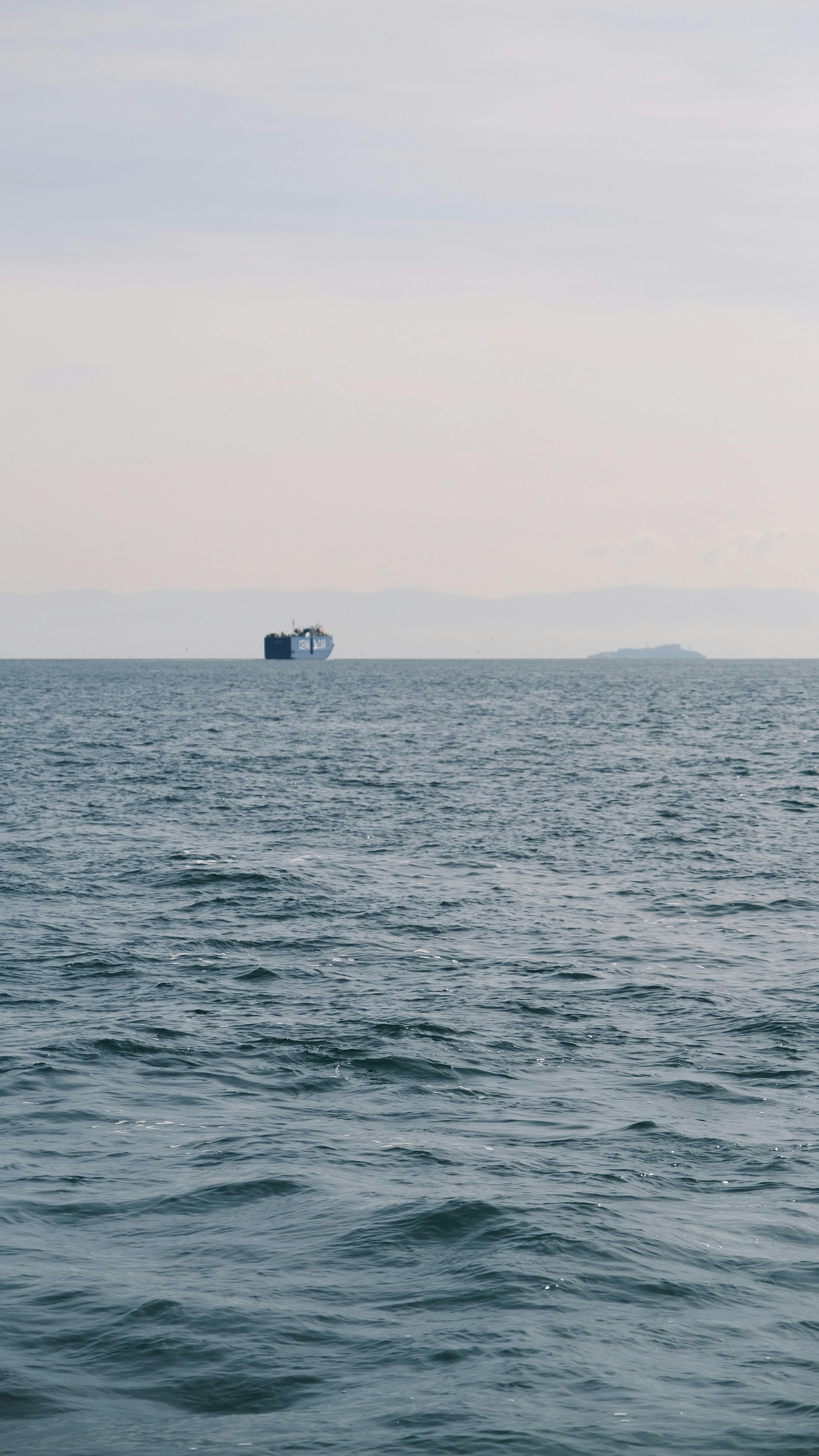 Distant Cargo Ship on Calm Sea Horizon · Free Stock Photo