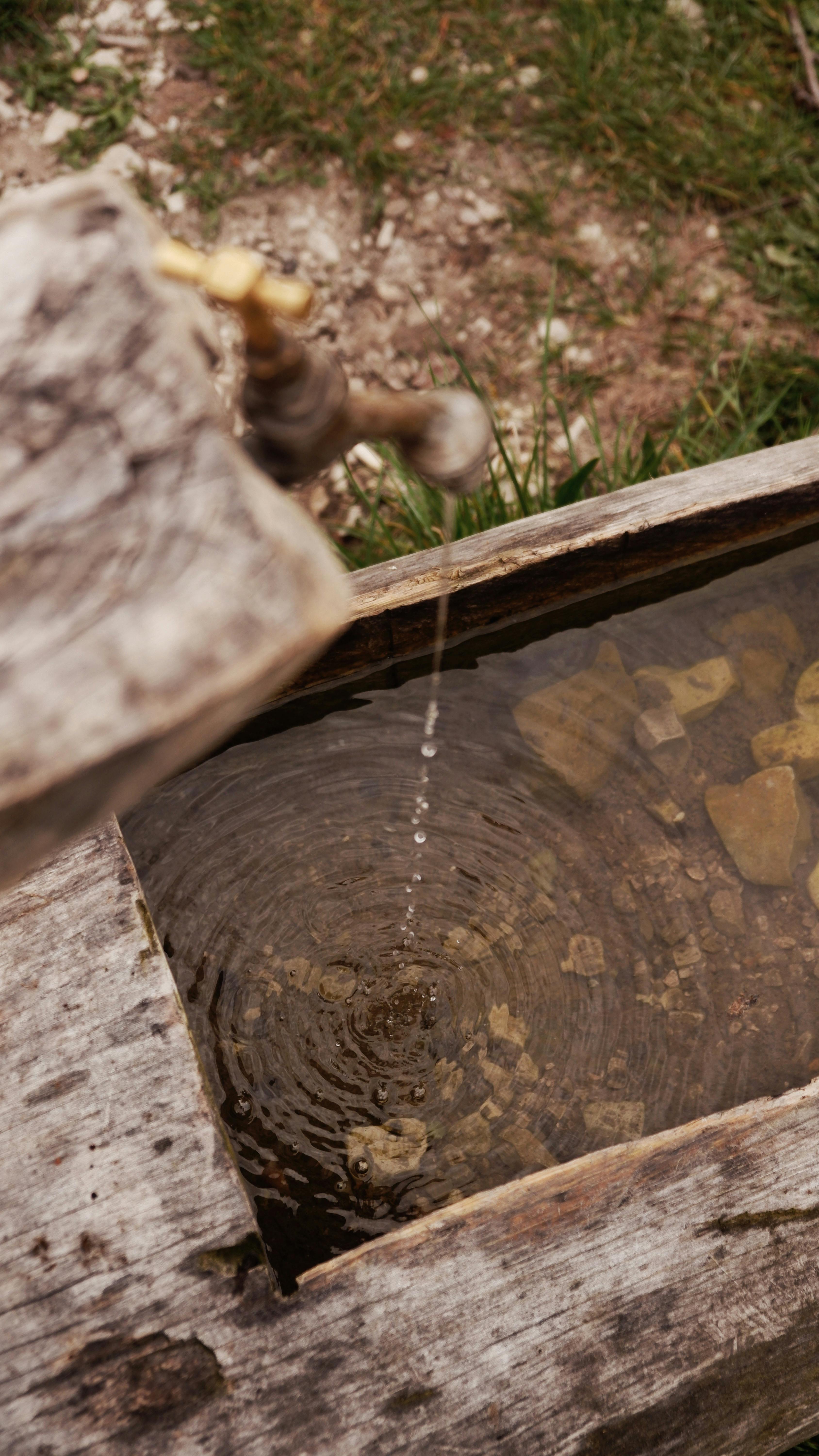 Rustic Wooden Water Trough with Flowing Tap Outdoors · Free Stock Photo