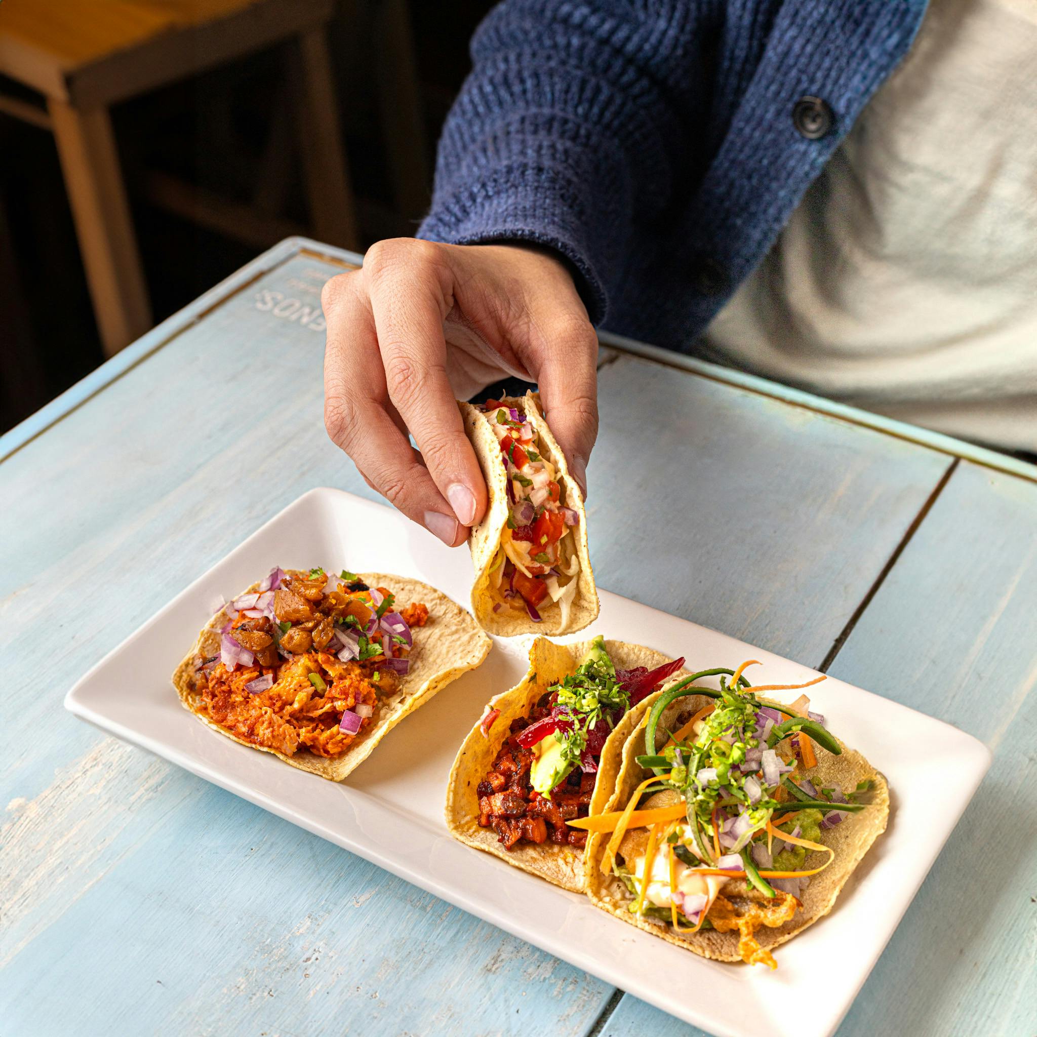 Person Enjoying Tacos with Fresh Ingredients · Free Stock Photo