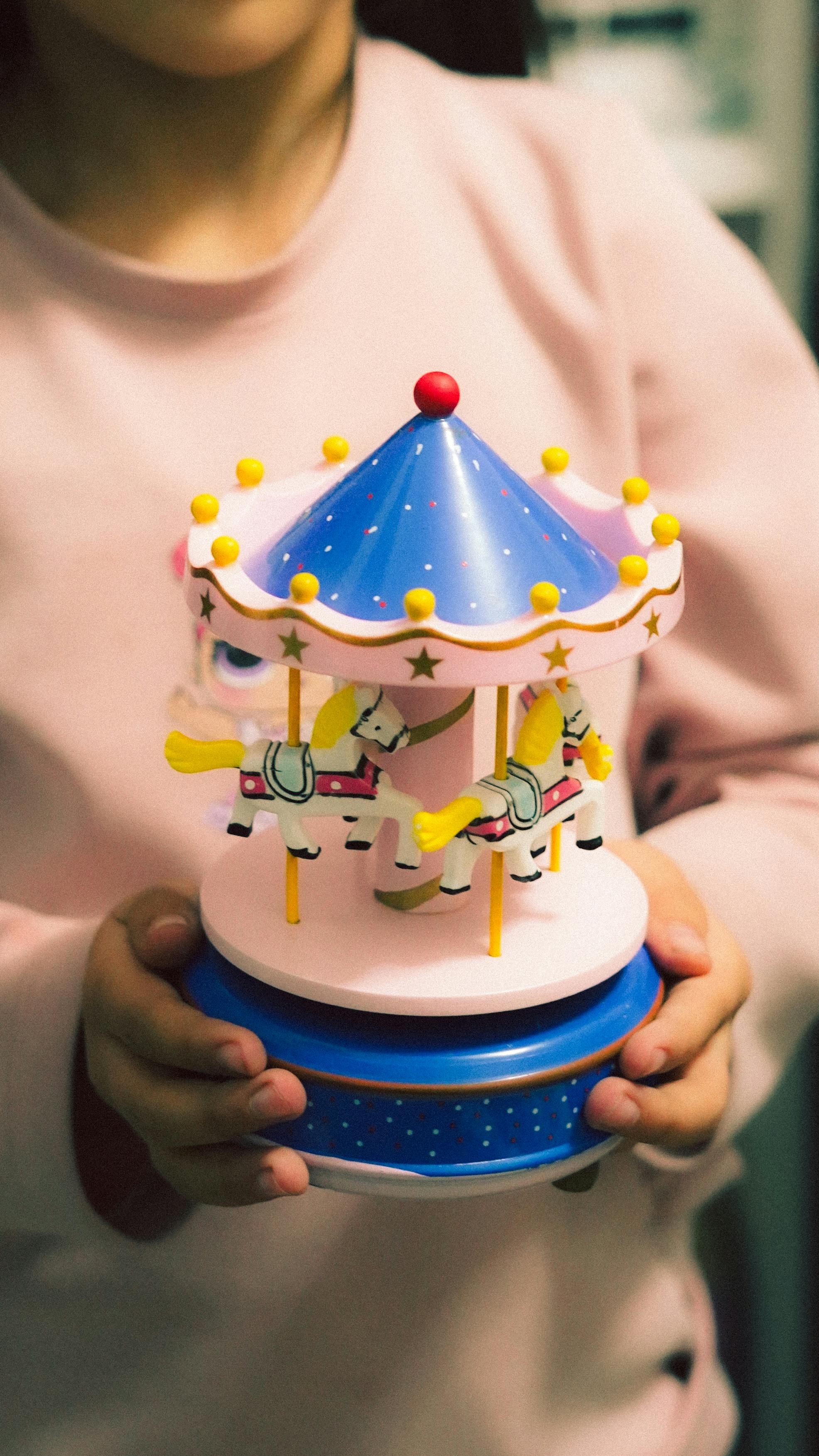 Colorful Miniature Carousel Music Box Held by Child · Free Stock Photo