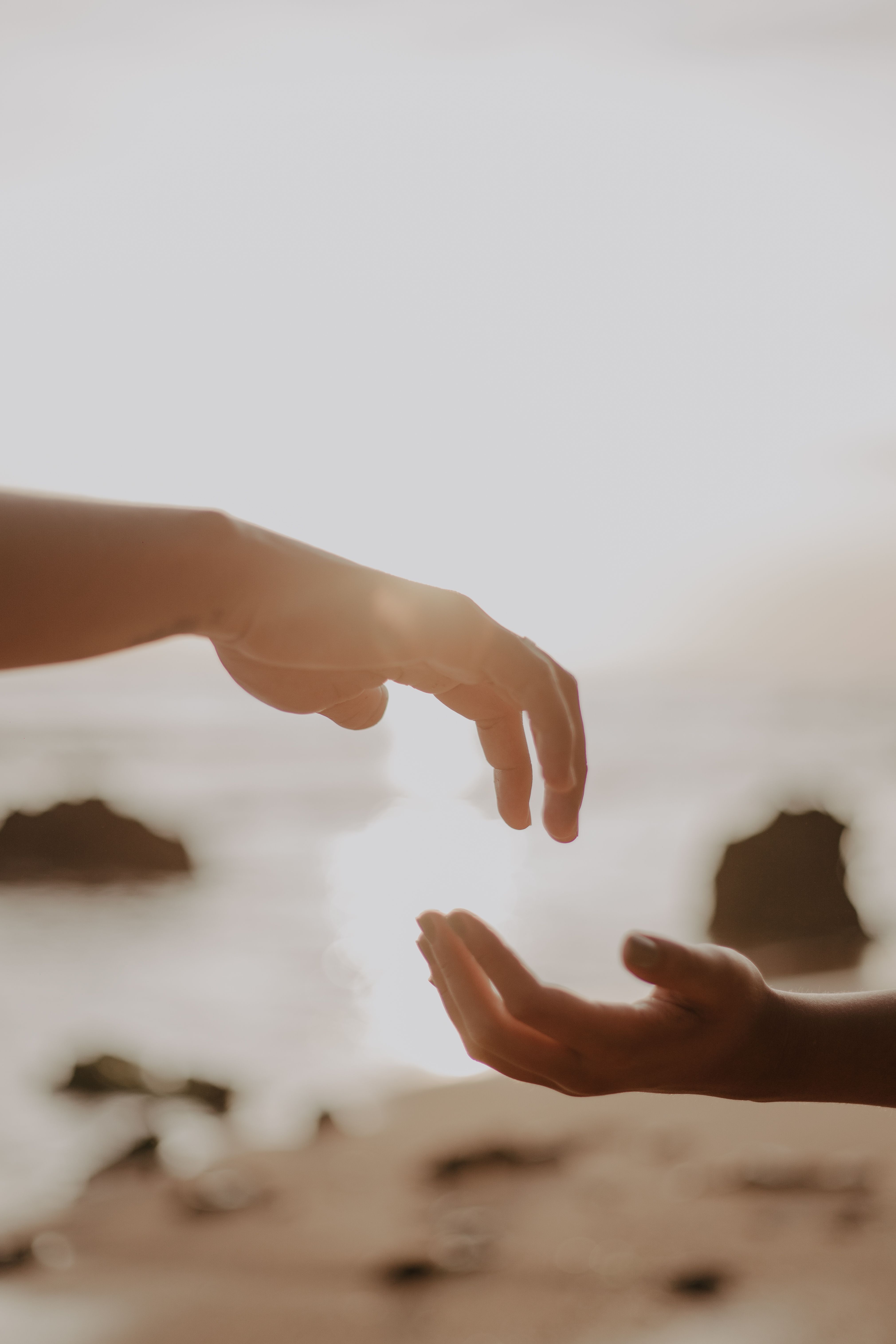Hands Reaching Out in Sunlit Beach Setting · Free Stock Photo