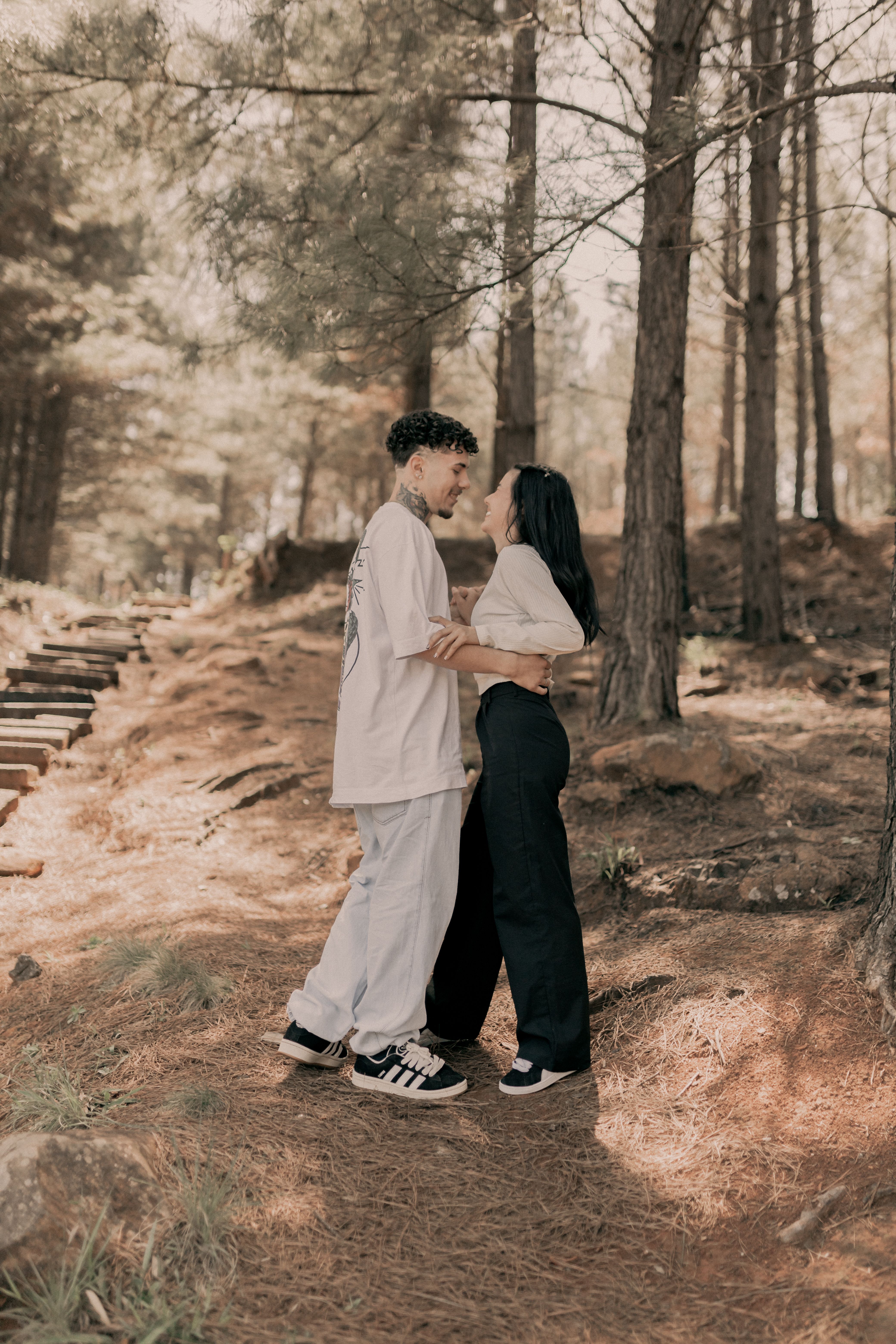 Young Couple Embracing in Sunlit Forest Path · Free Stock Photo