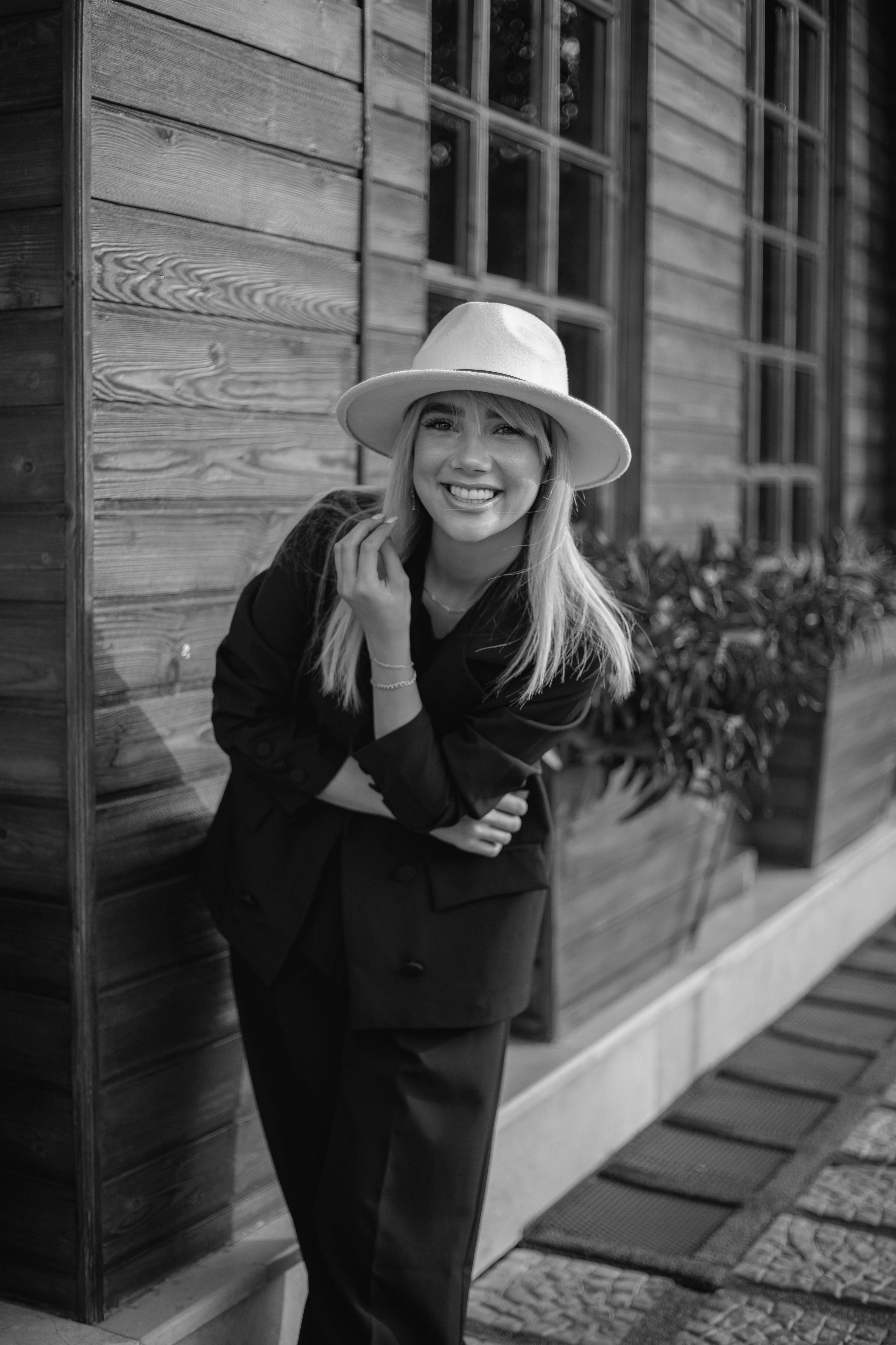 Stylish Woman in White Hat Leaning Against Wooden Wall · Free Stock Photo