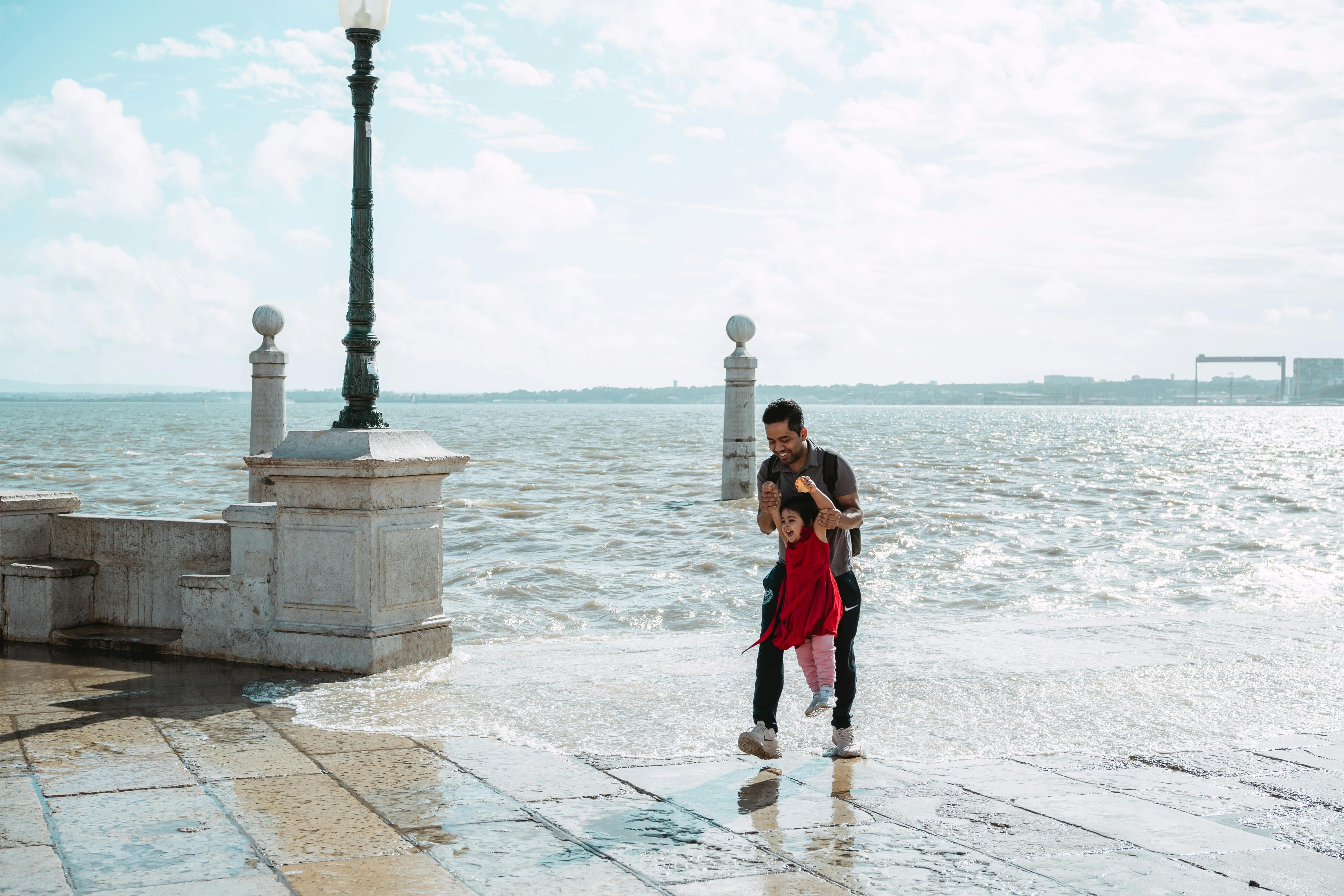Father and Daughter Enjoying Waterfront Walk · Free Stock Photo