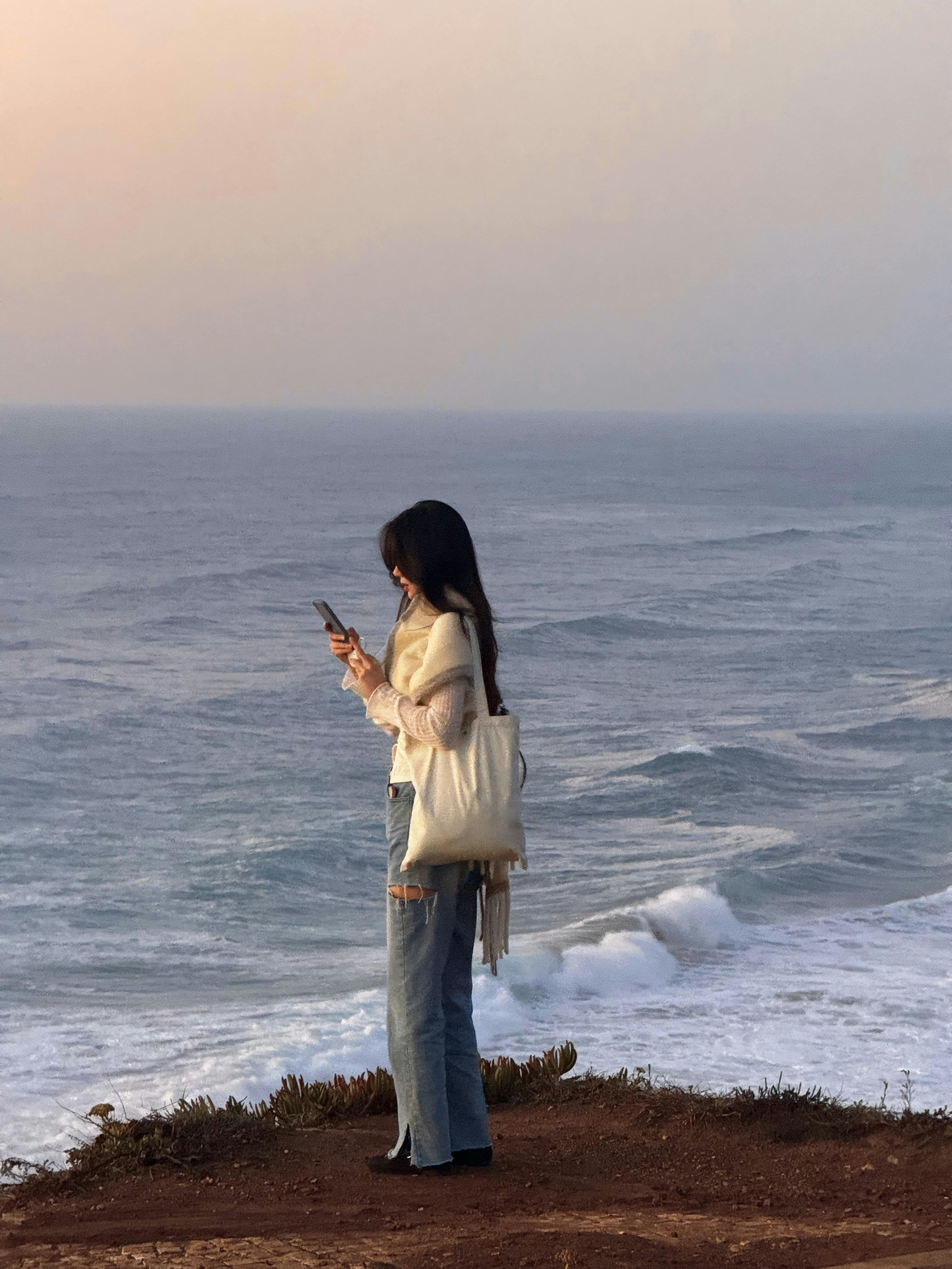 Woman on Cliffside Overlooking Ocean at Sunset · Free Stock Photo