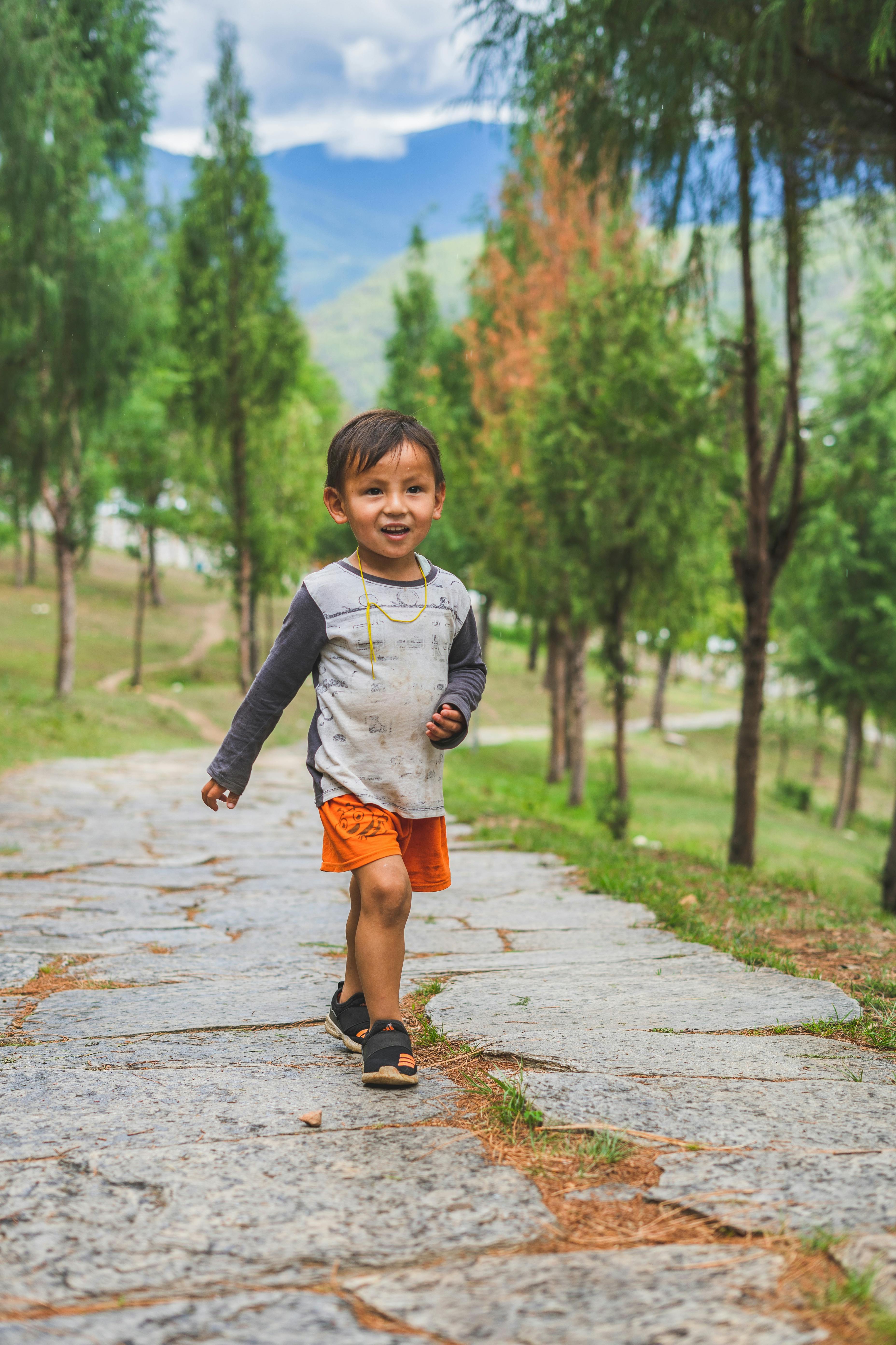 Smiling Child Walking on Stone Path Outdoors · Free Stock Photo