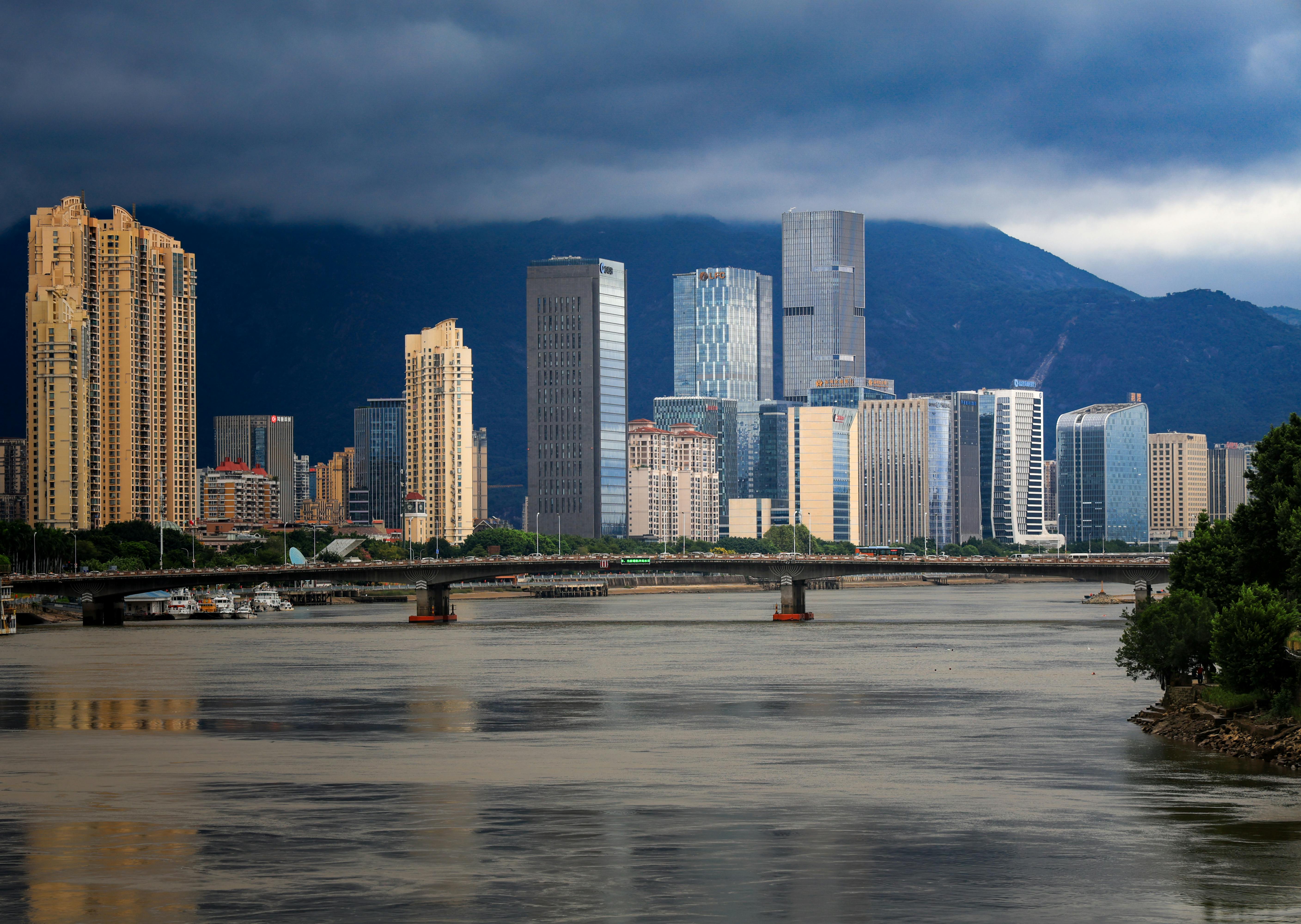 Dramatic City Skyline with River and Clouds · Free Stock Photo