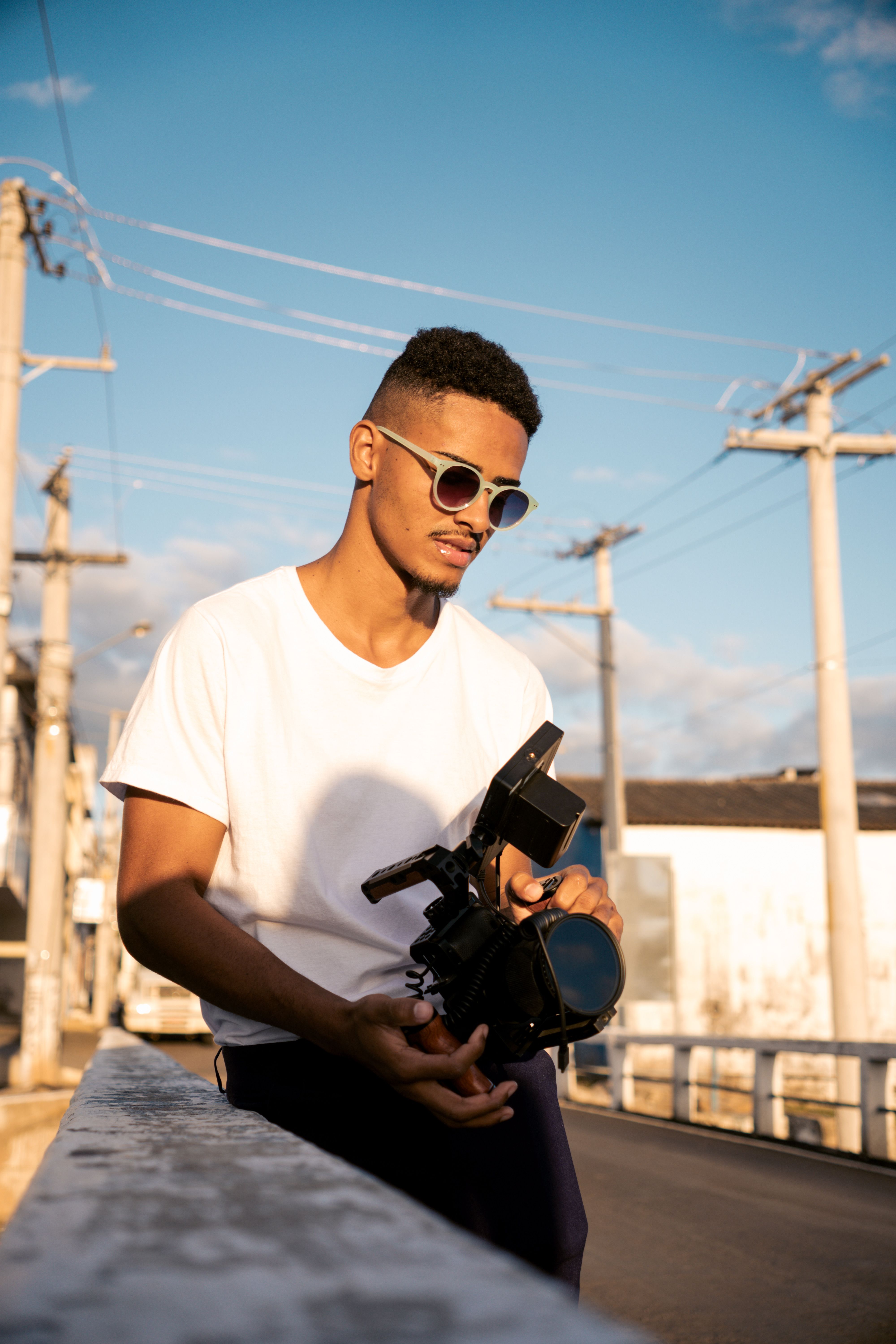 Young Filmmaker Holding Camera Outdoors · Free Stock Photo