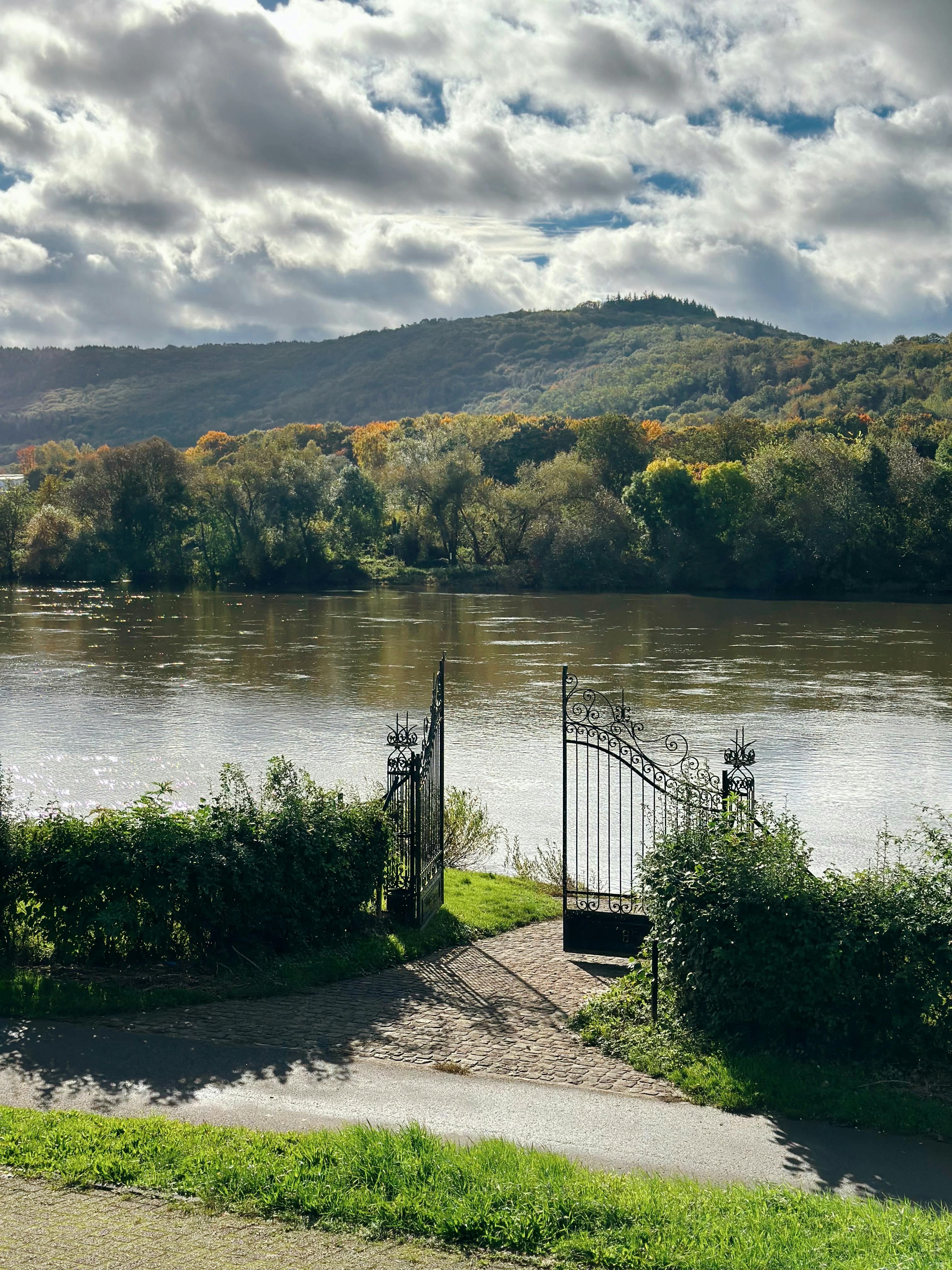 Scenic River View with Open Garden Gate · Free Stock Photo
