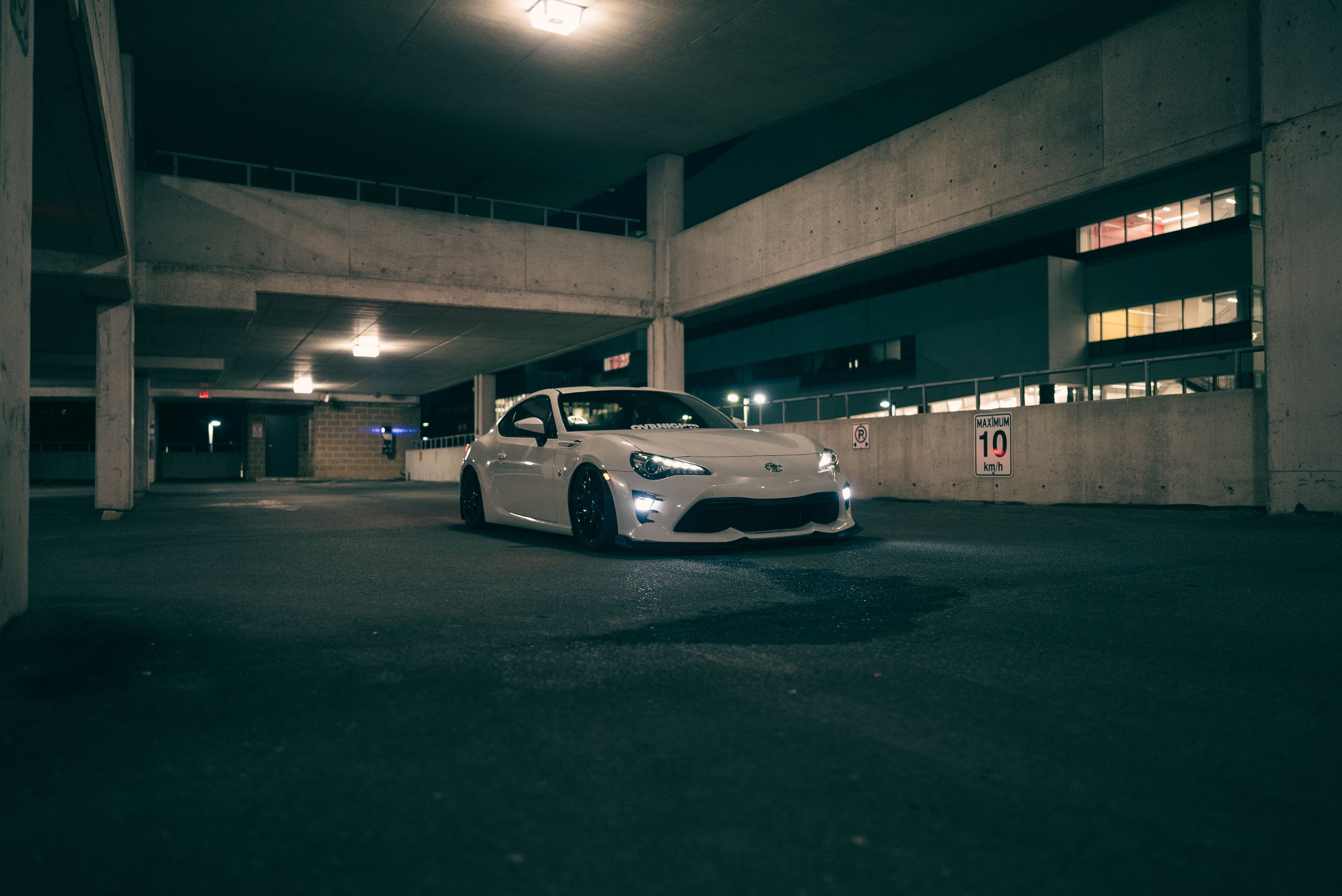 Sleek White Sports Car in Dimly Lit Parking Garage · Free Stock Photo