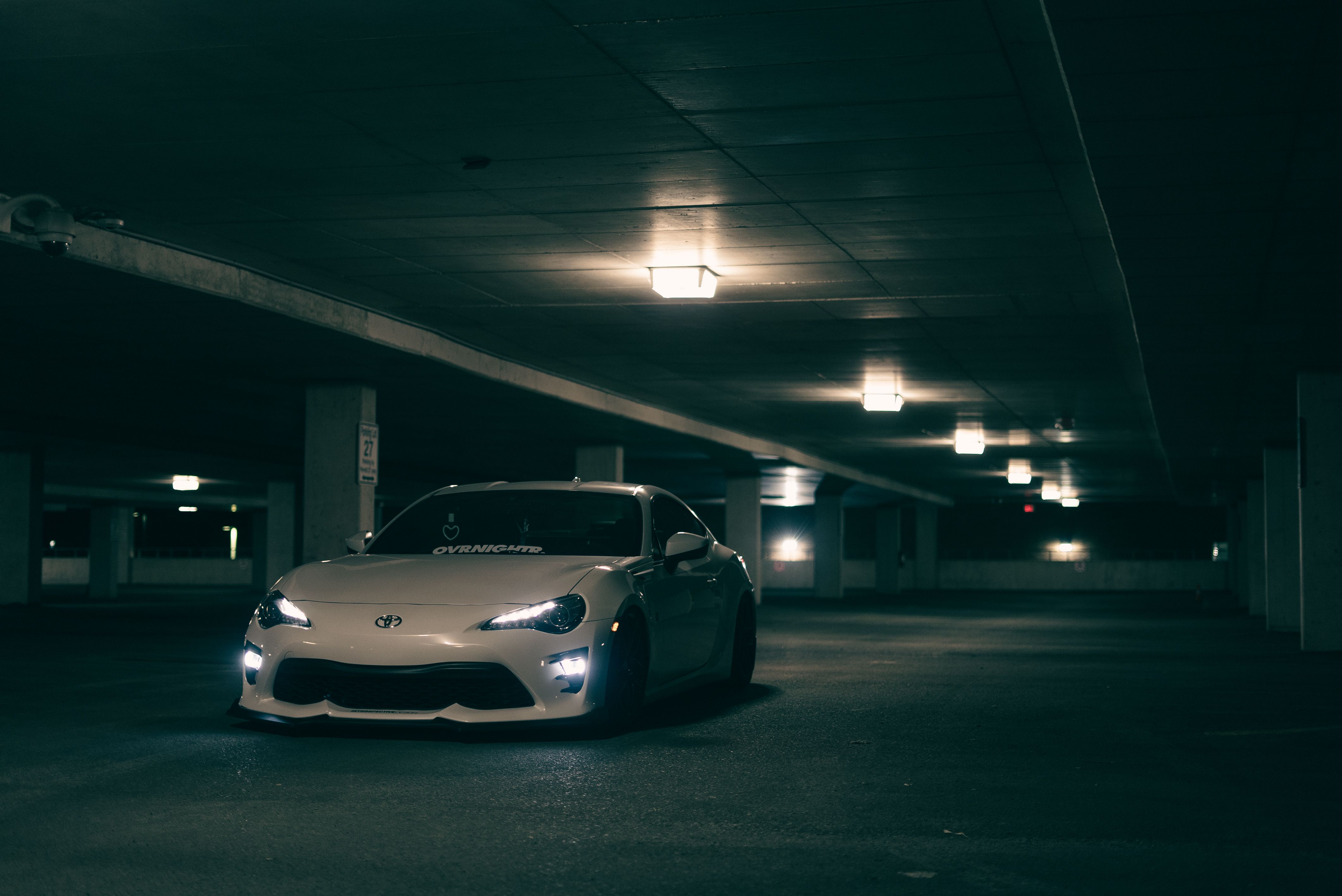 Sleek White Car Parked in Dimly Lit Garage · Free Stock Photo