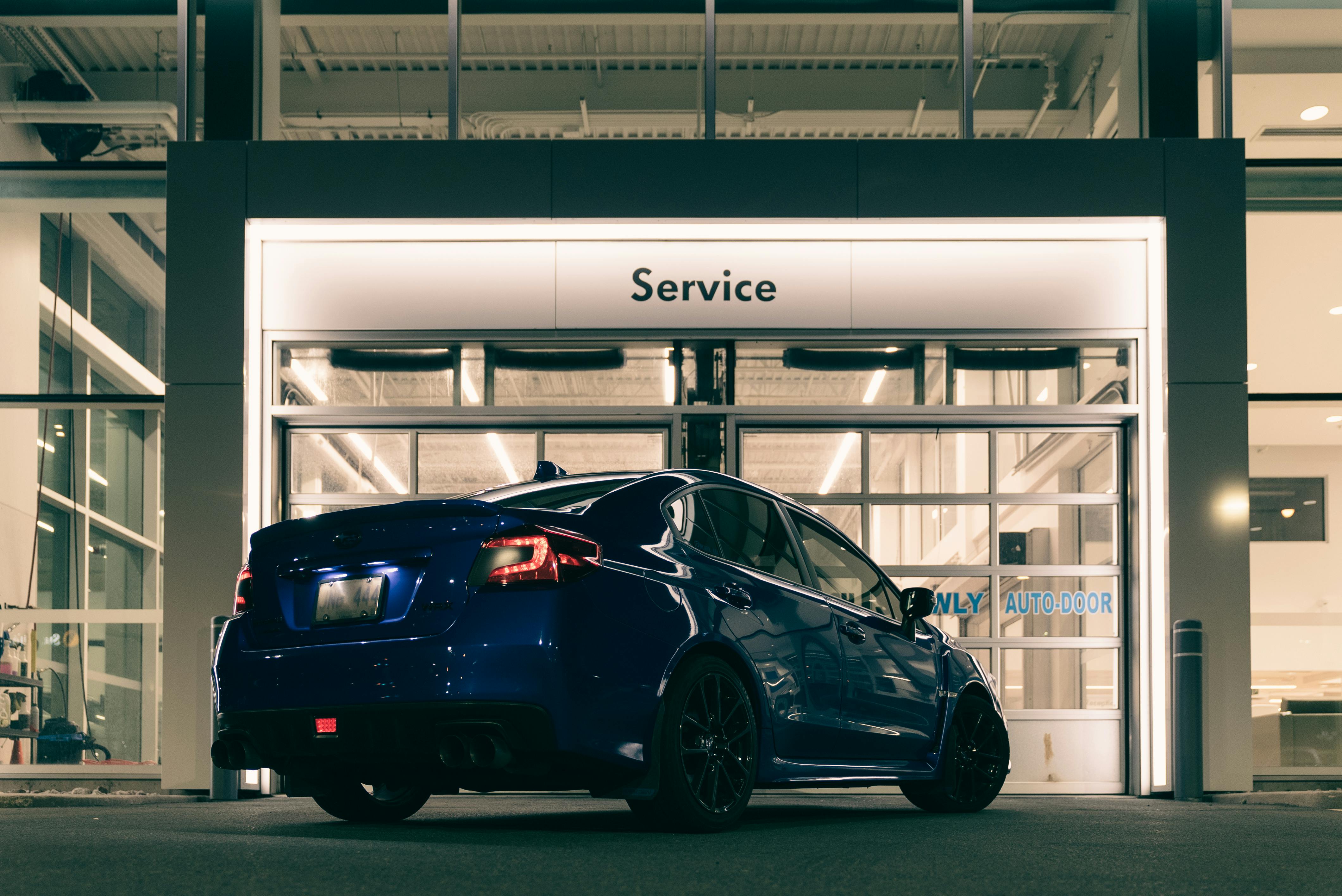 Blue Car at Night in Front of Auto Service Center · Free Stock Photo