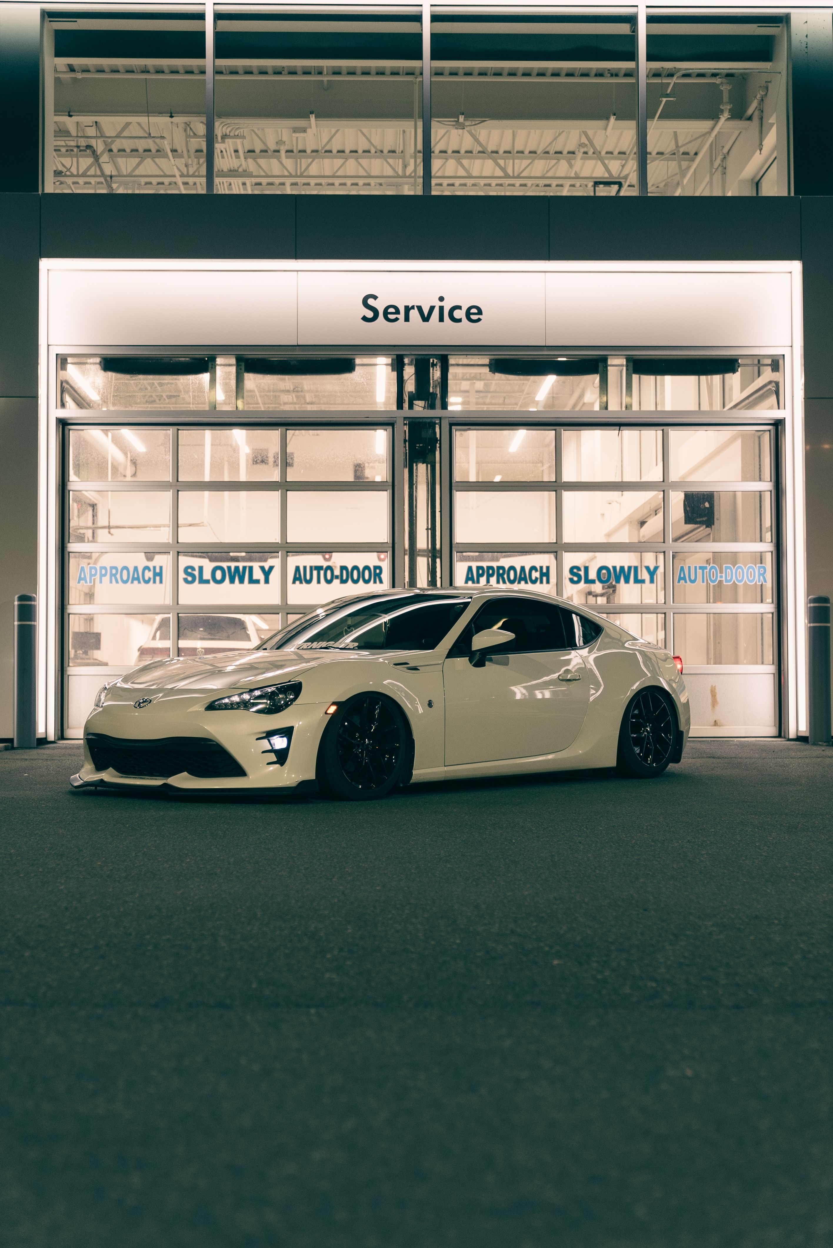 Sleek White Car at Auto Service Entrance · Free Stock Photo
