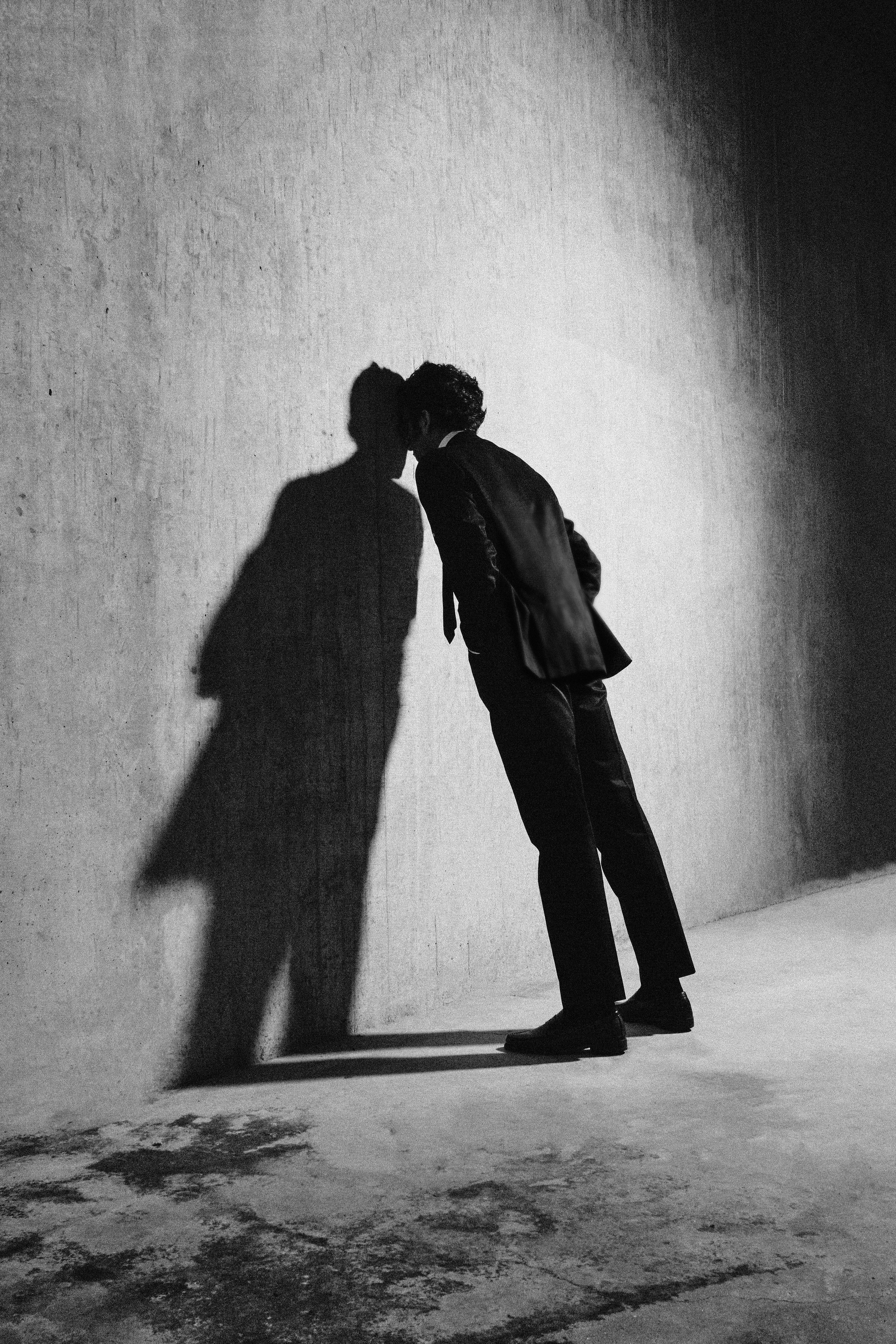 Mysterious Man in Suit Inspecting Shadow on Wall · Free Stock Photo
