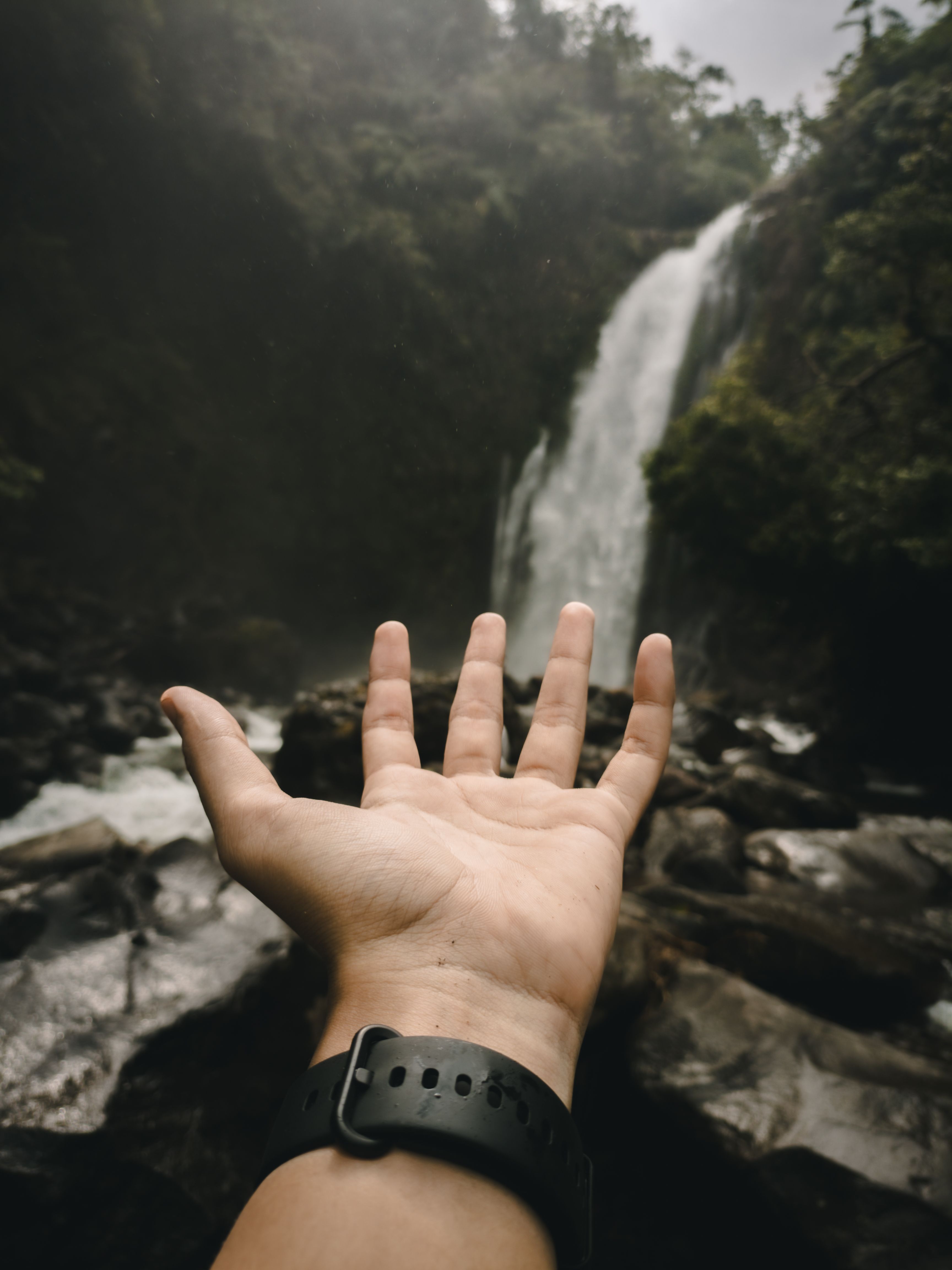 Reaching Hand Towards Serene Waterfall Outdoors · Free Stock Photo