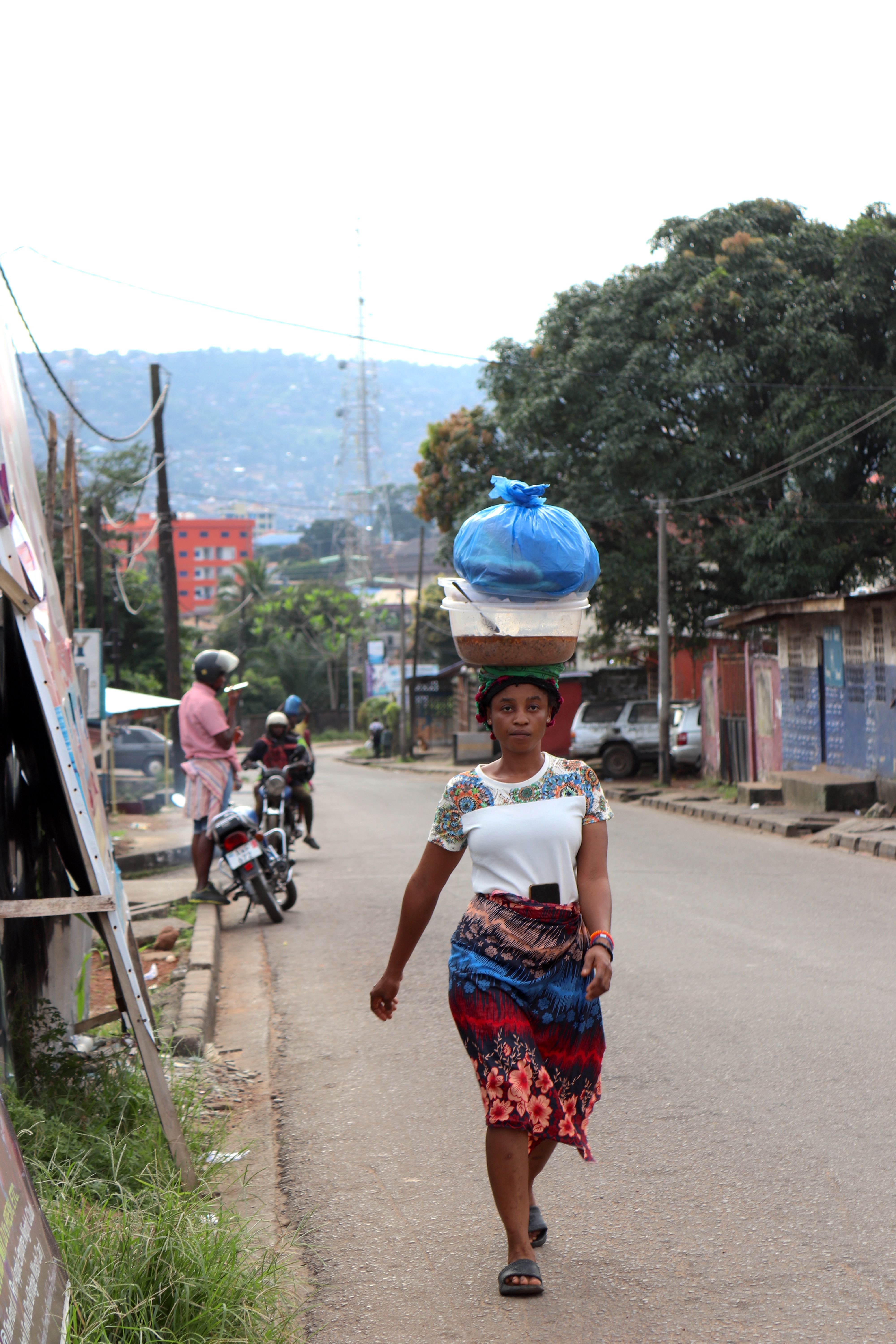 Woman Balancing Goods on Head in City Street · Free Stock Photo