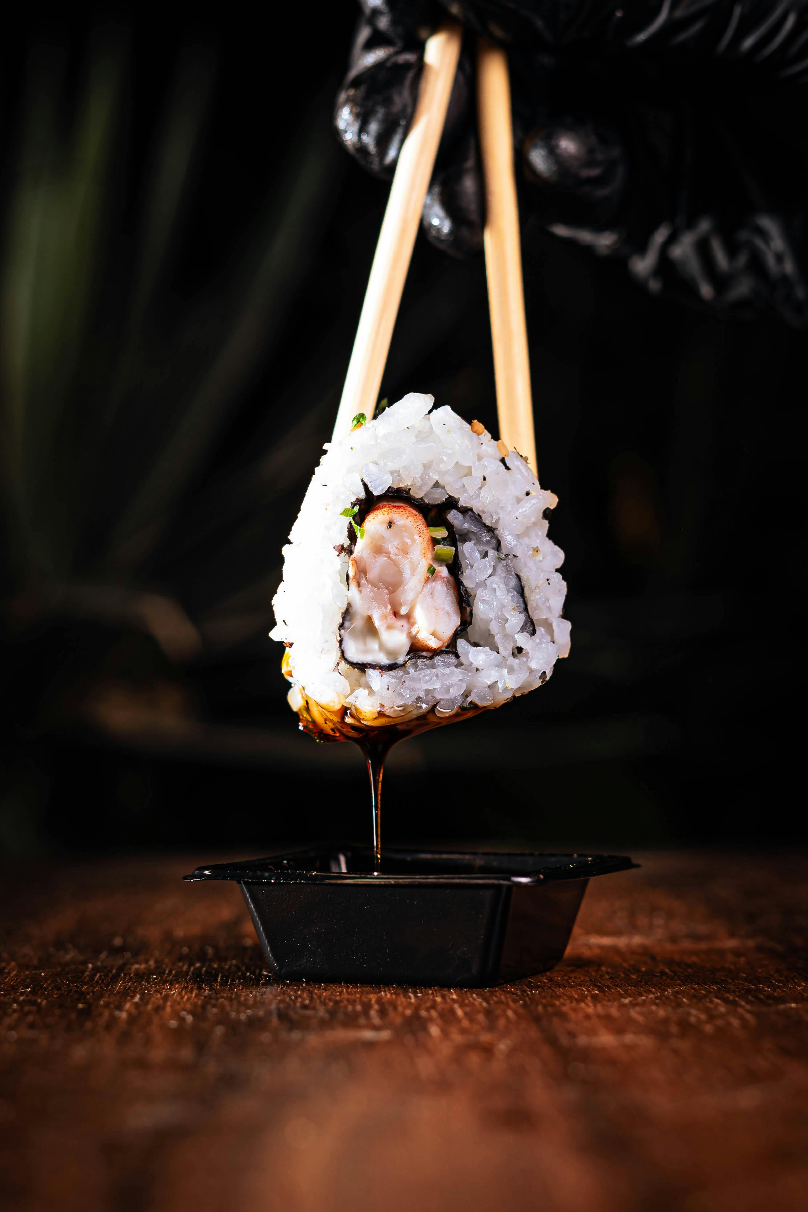 Sushi Roll Dripping Soy Sauce with Chopsticks · Free Stock Photo