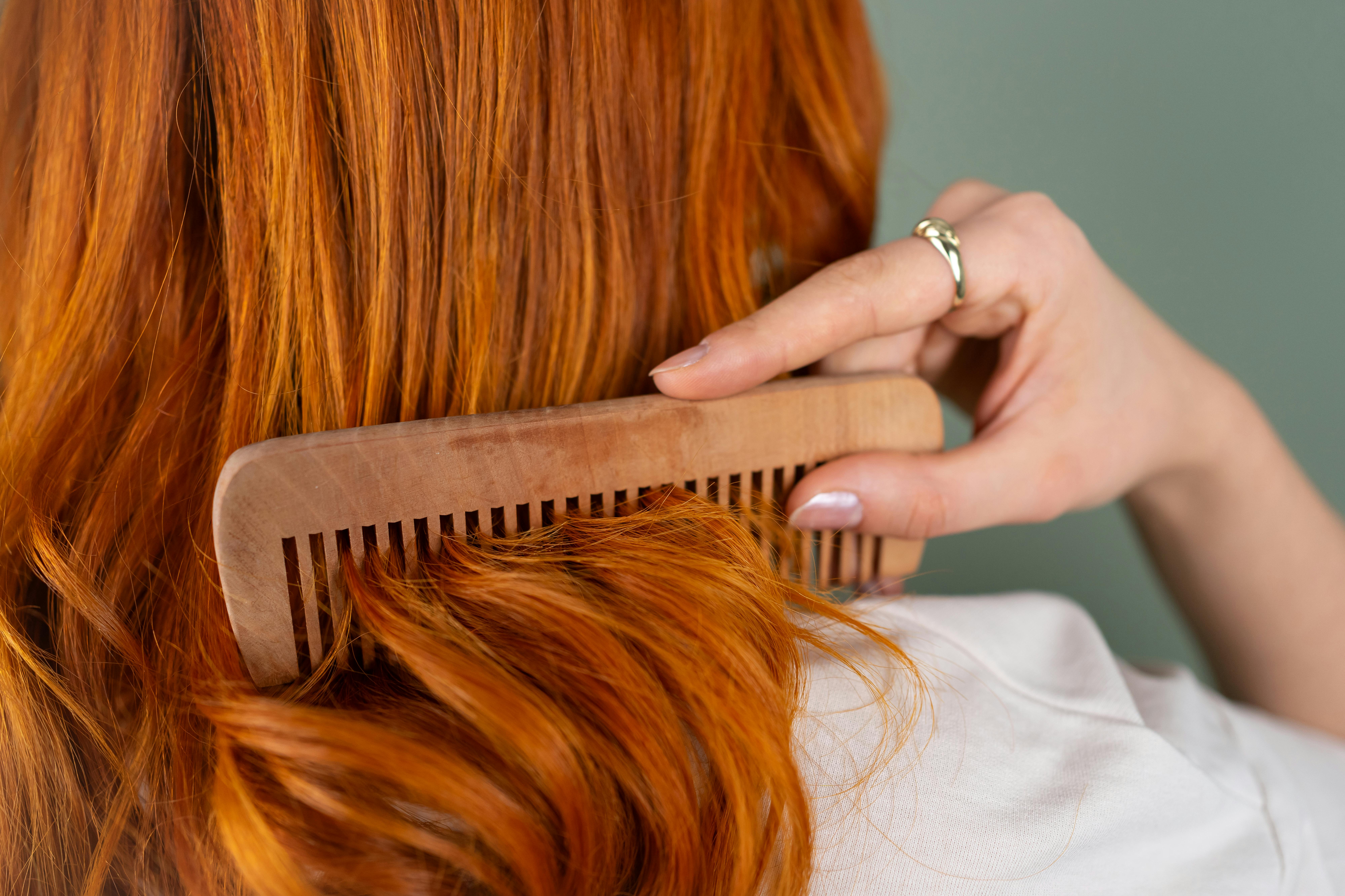 Woman Combing Long Red Hair with Wooden Comb · Free Stock Photo
