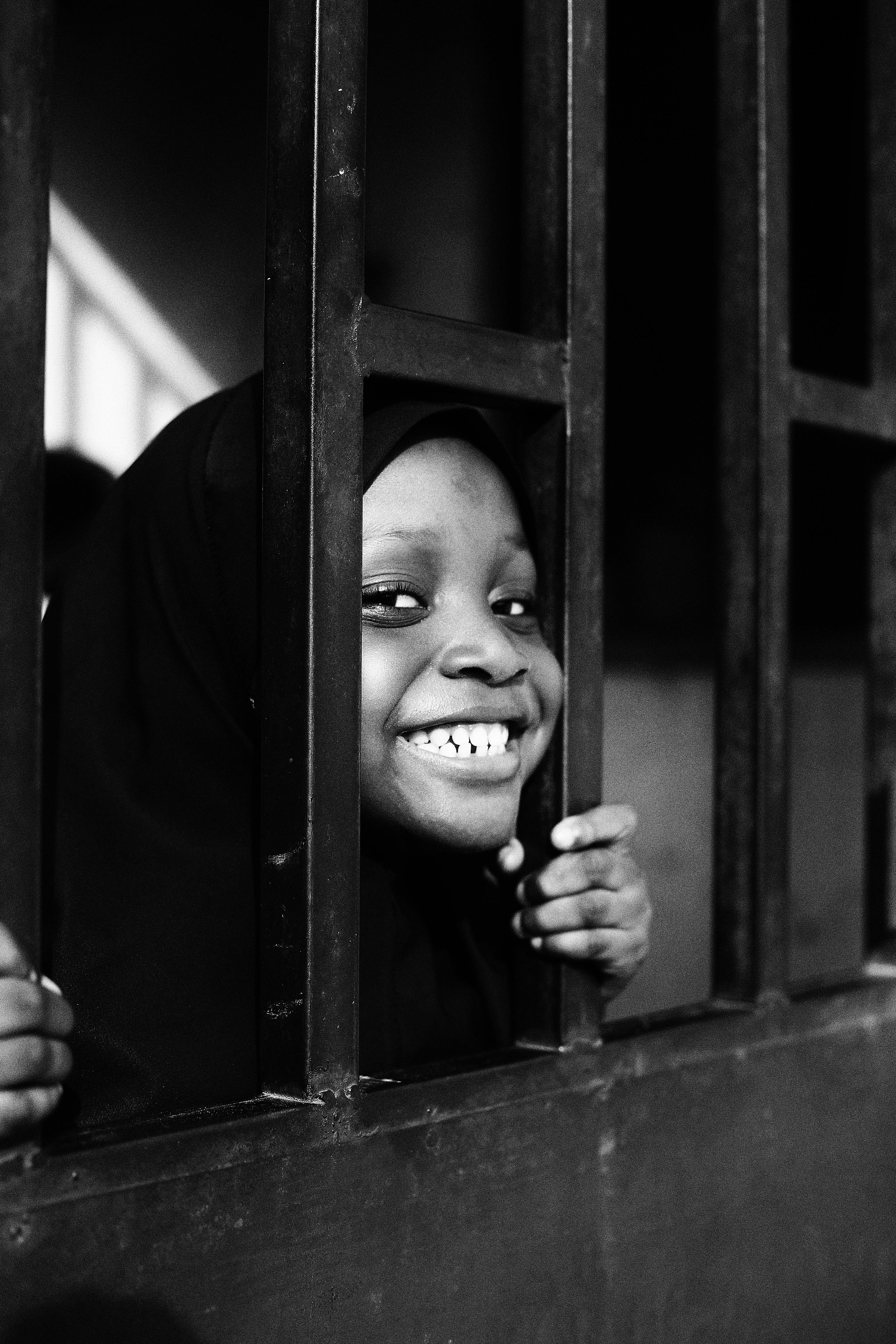 Anak Tersenyum Berhijab Di Balik Jeruji Besi · Foto Stok Gratis