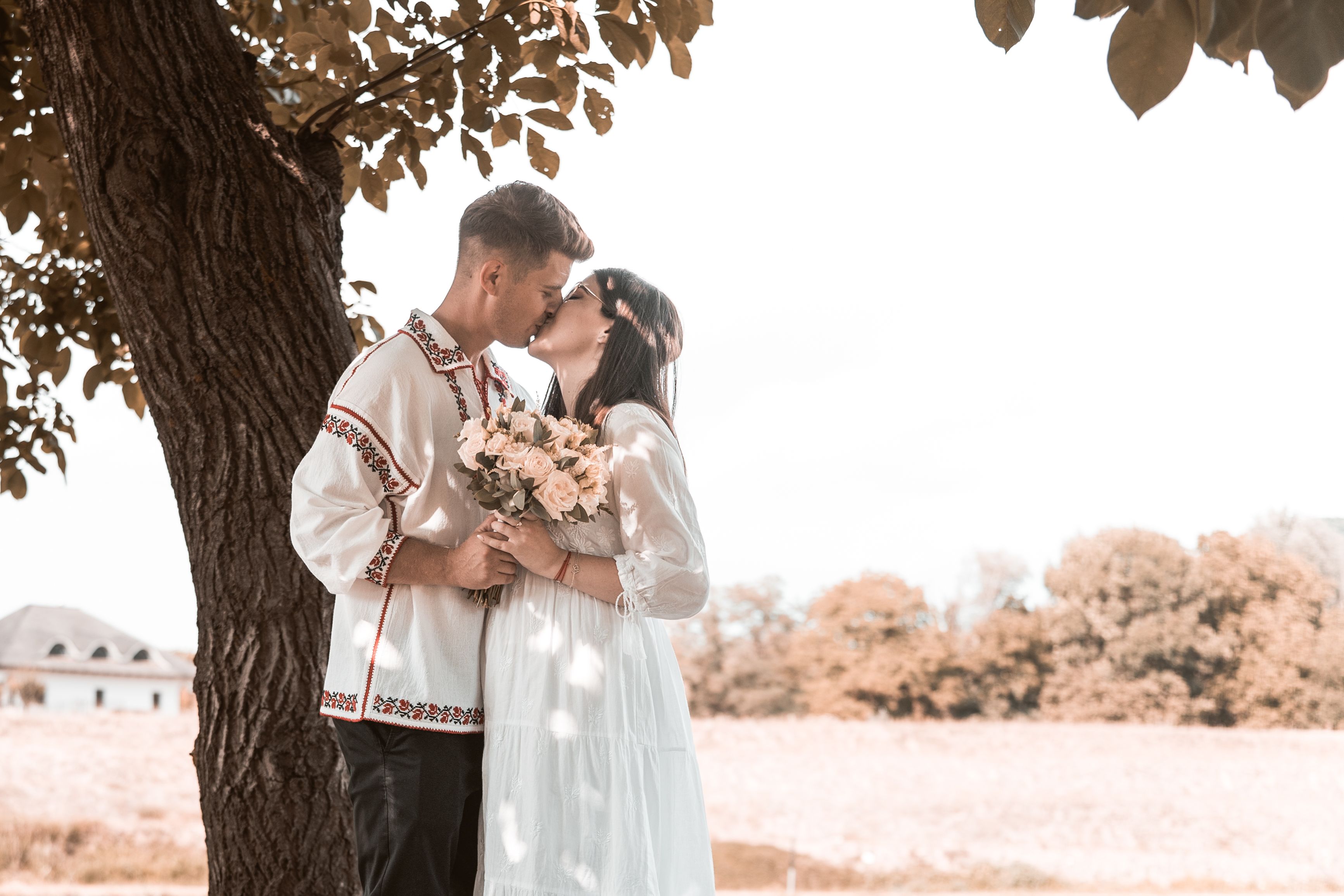 Romantic Couple Kissing Under Tree Outdoors · Free Stock Photo