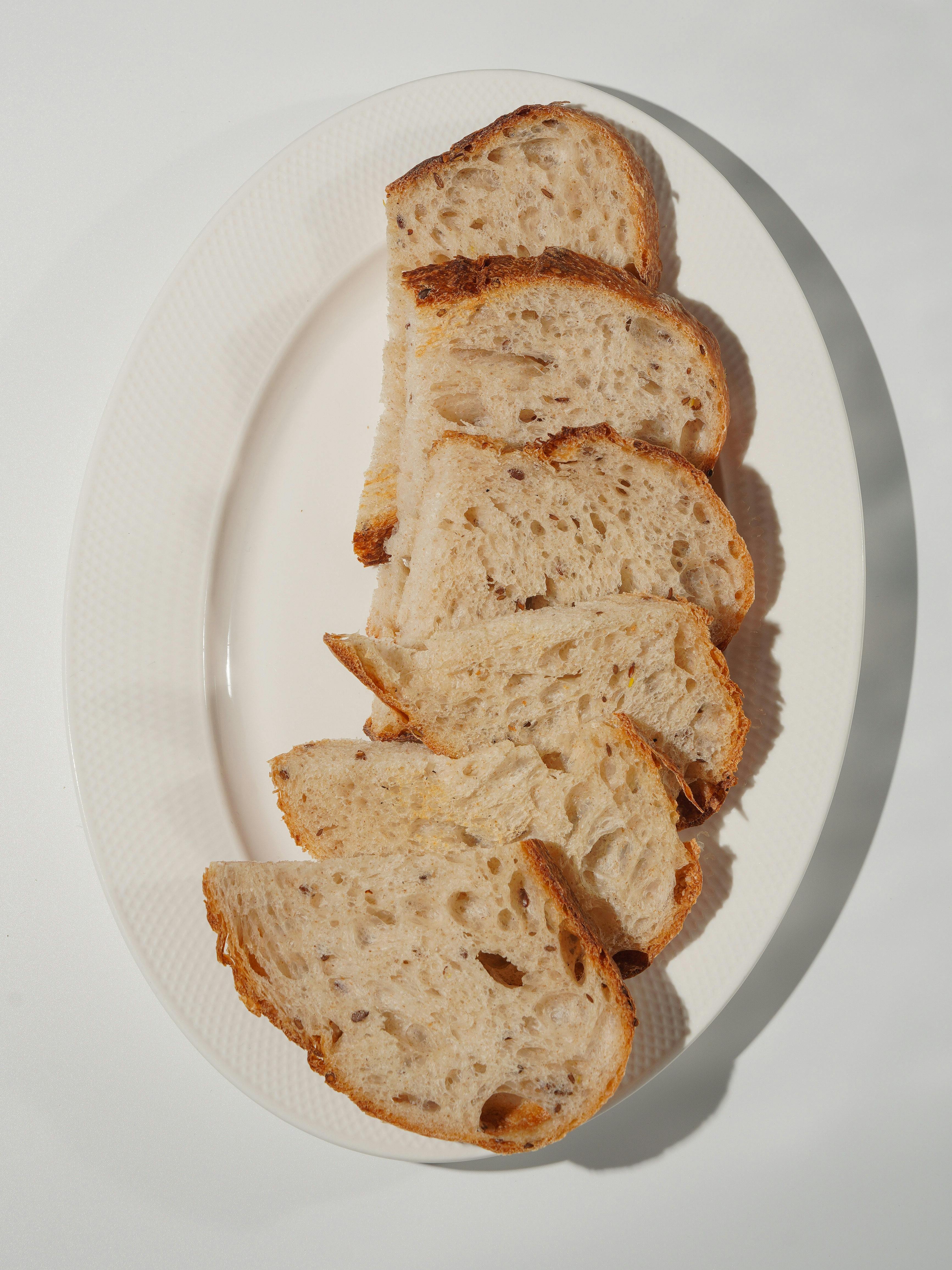 Sliced Rustic Bread on White Plate Top View · Free Stock Photo