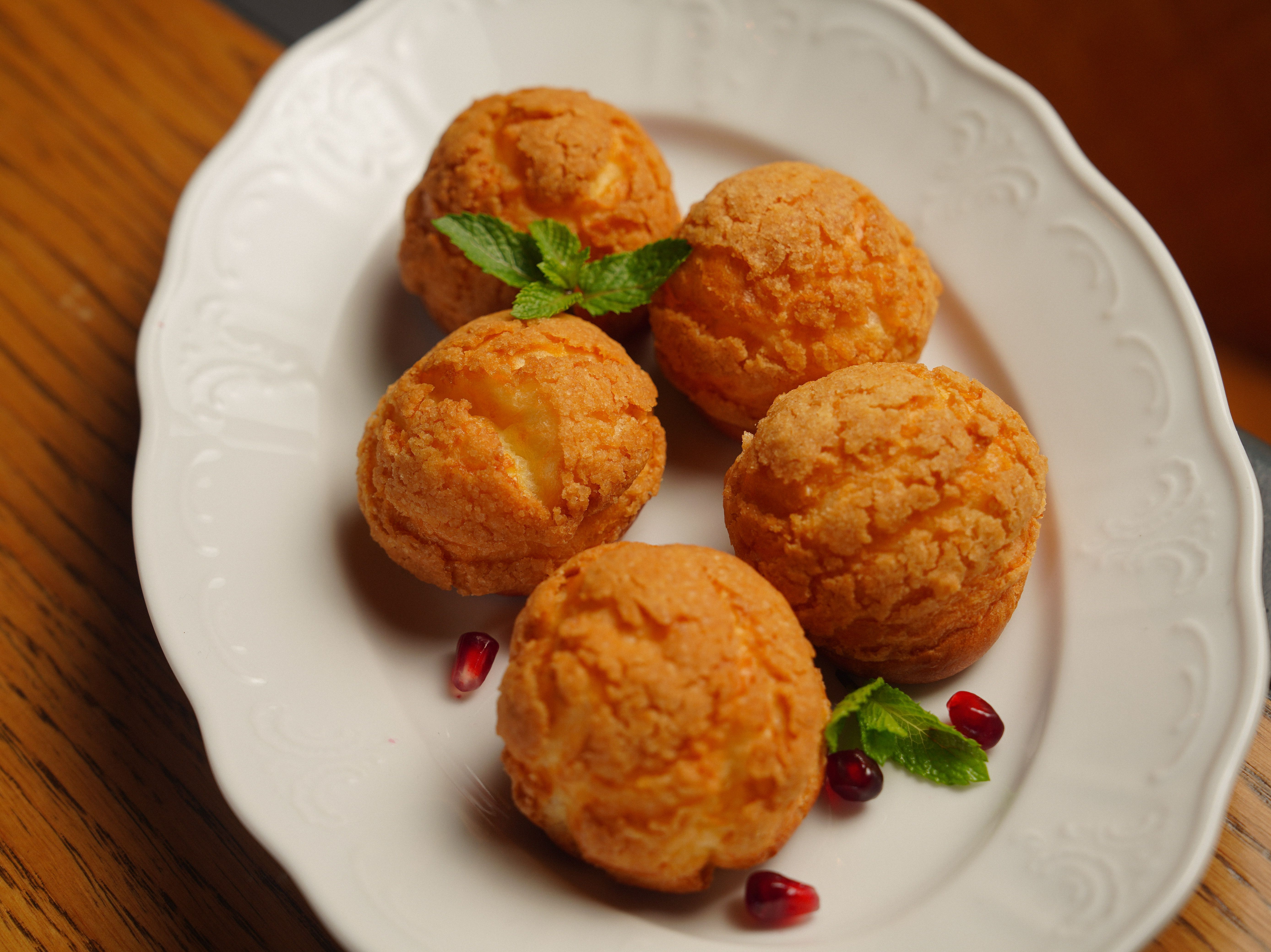Golden pastry puffs served on ornate white plate · Free Stock Photo