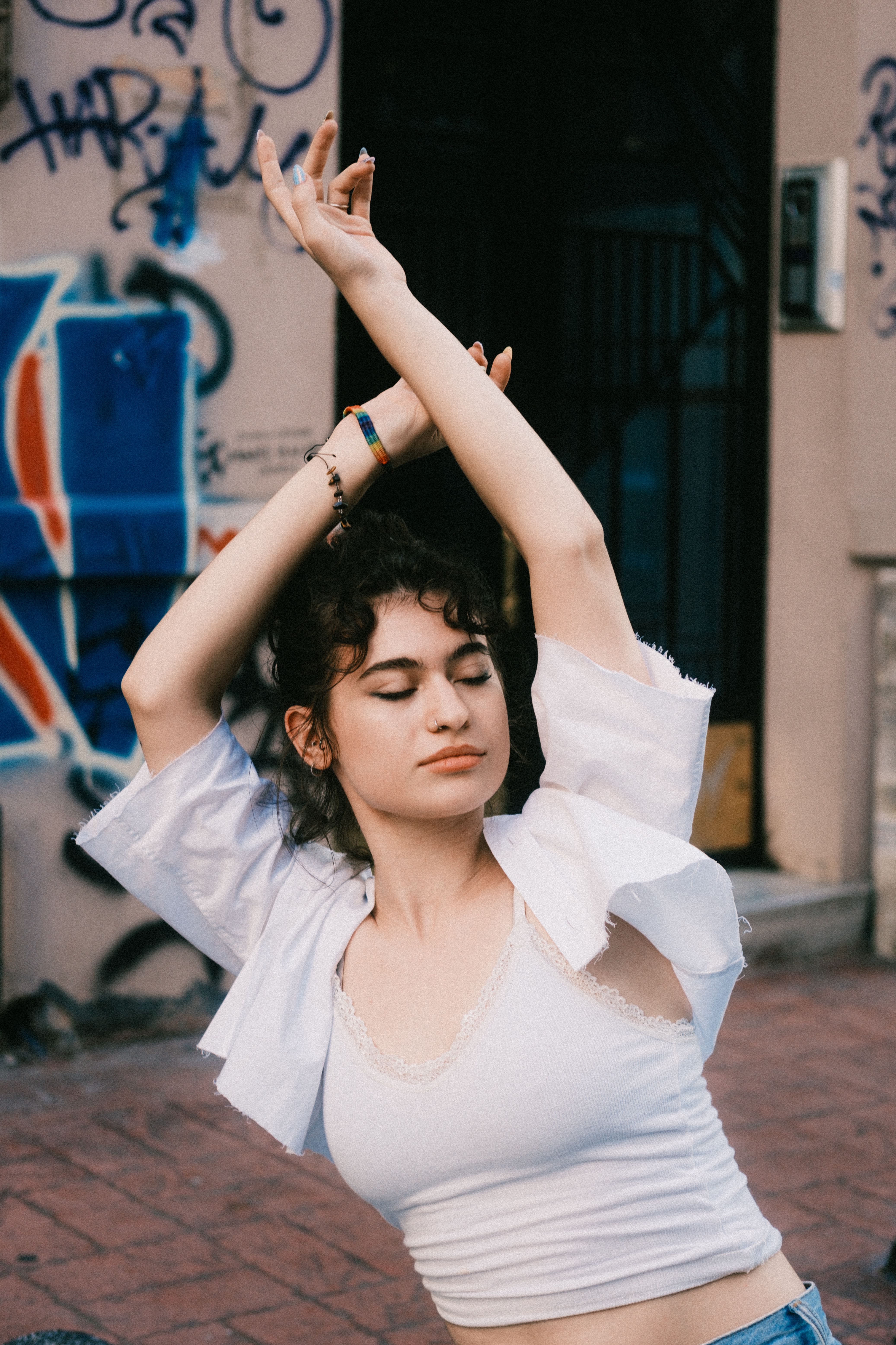 Young Woman Posing with Arms Raised in Urban Setting · Free Stock Photo