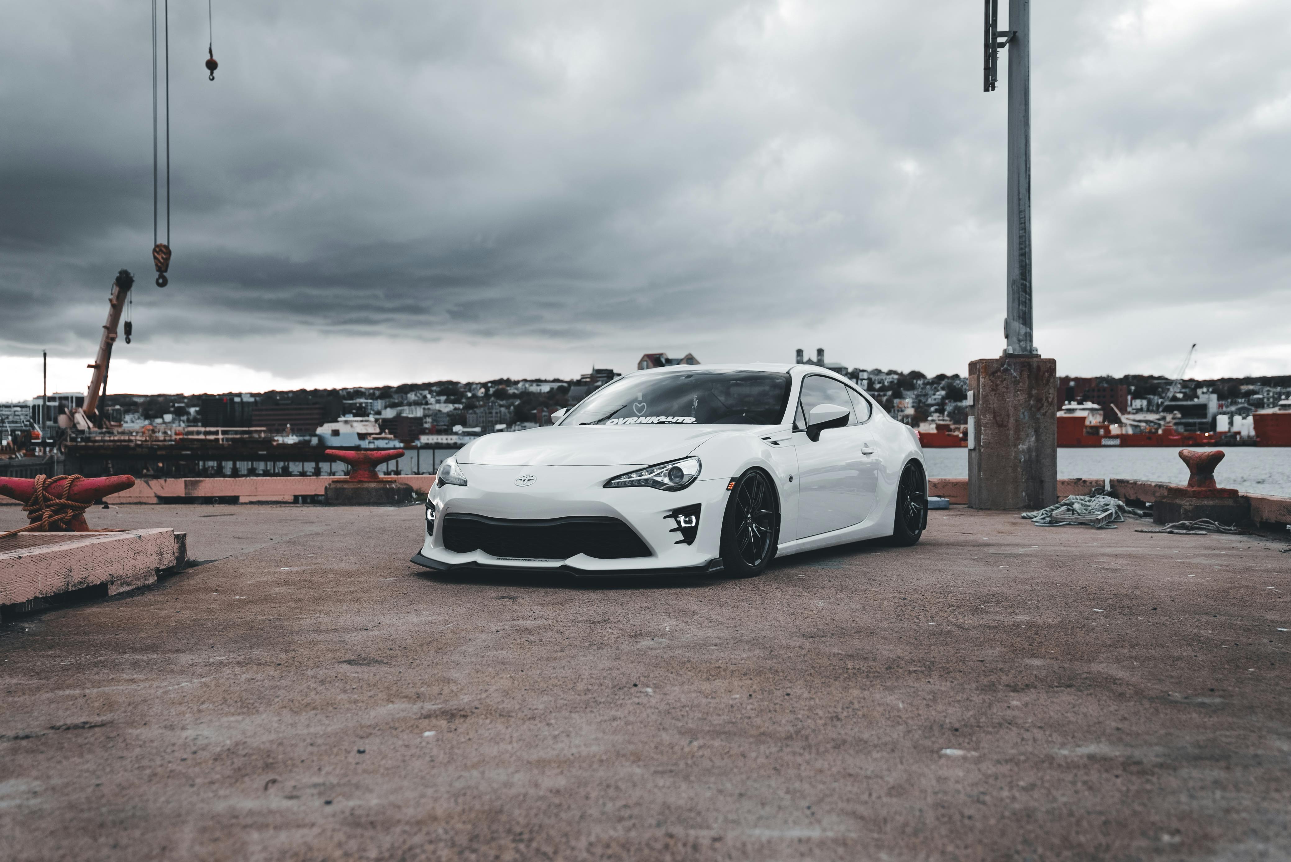 Sleek White Sports Car on Harbor Dock · Free Stock Photo