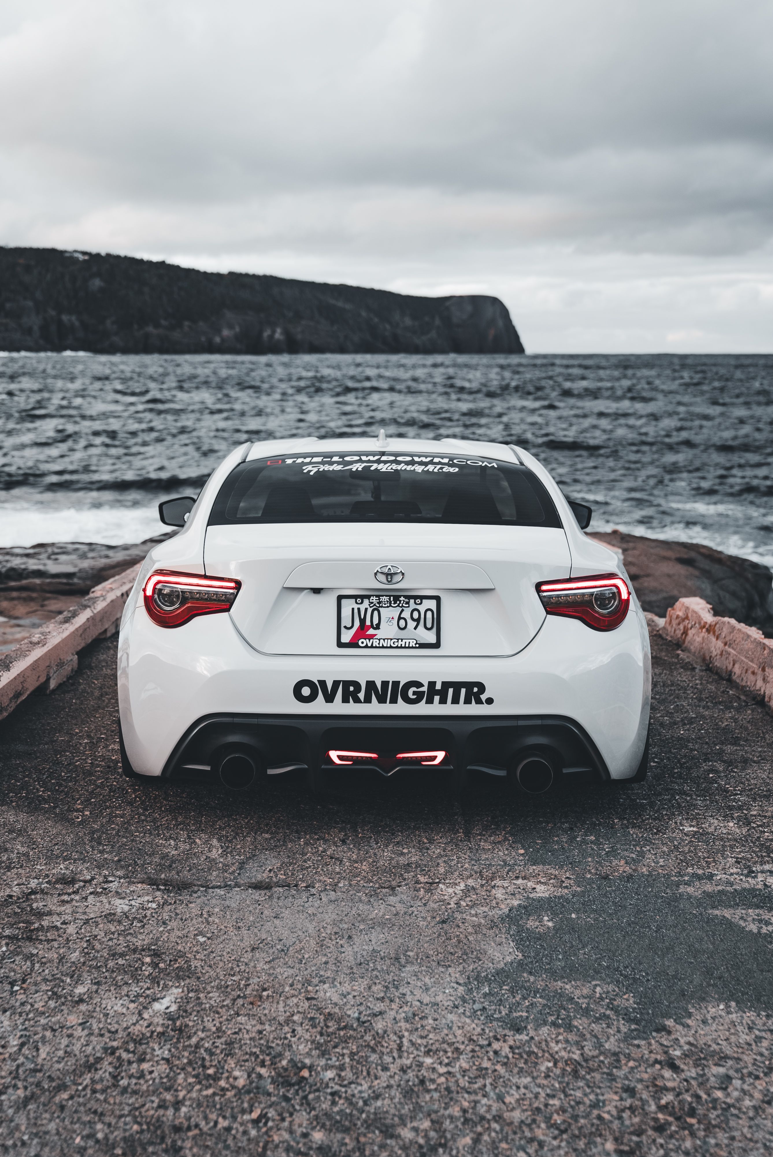 Sporty White Car on Coastal Road with Ocean View · Free Stock Photo