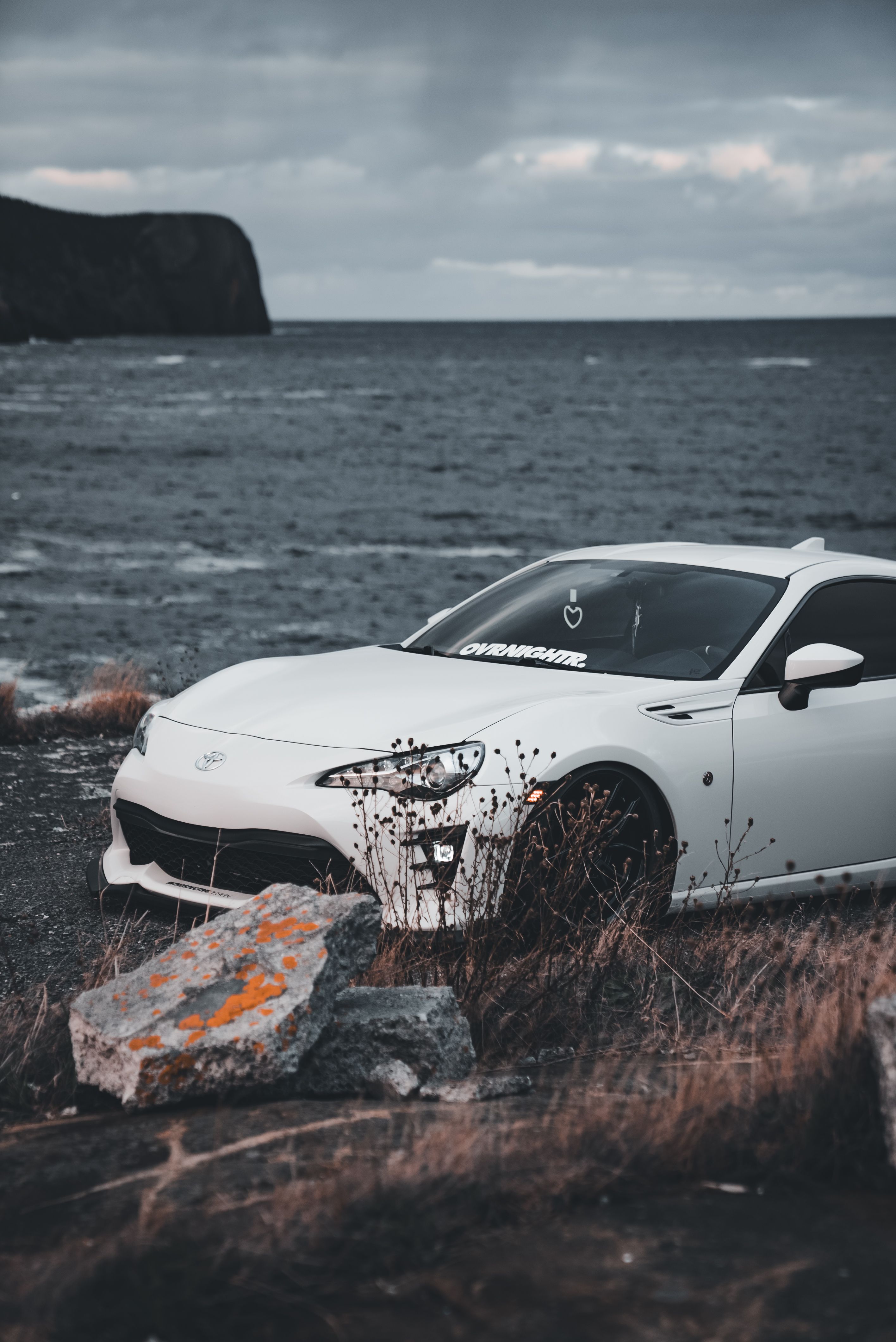 White Sports Car by a Rugged Ocean Coastline · Free Stock Photo