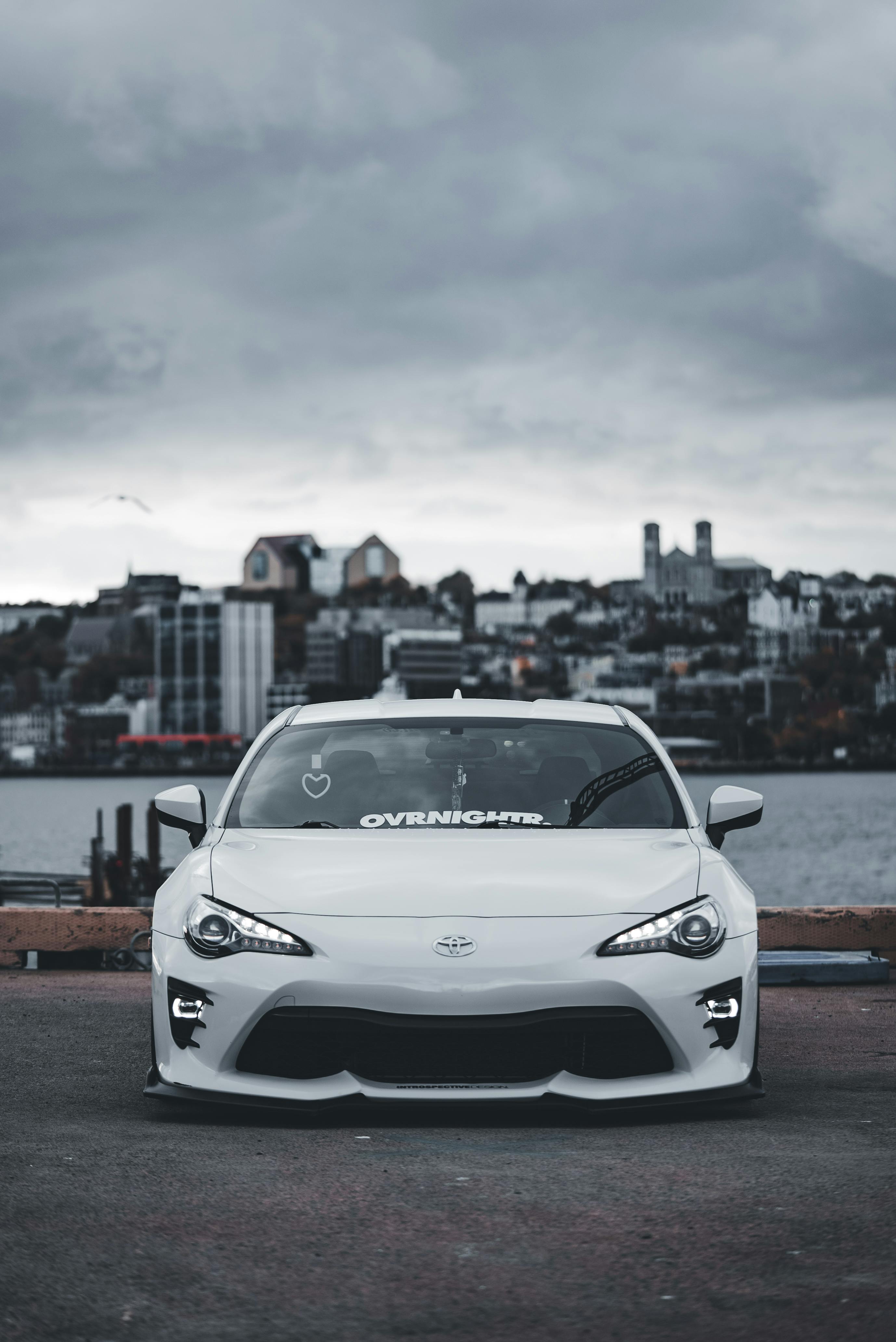 Stylish White Car Front Against Urban Backdrop · Free Stock Photo