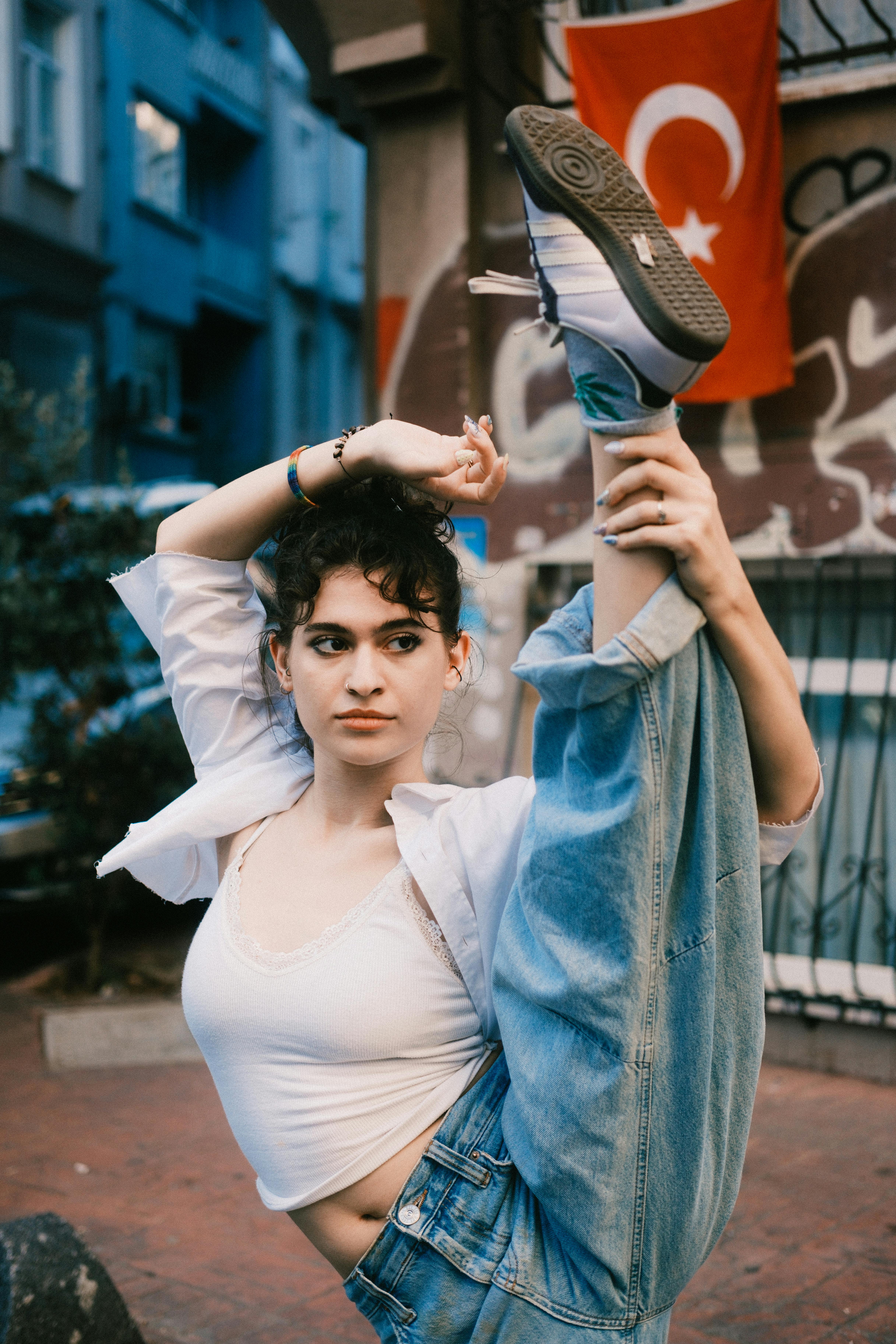 Young Woman Performing High Leg Stretch Outdoors · Free Stock Photo