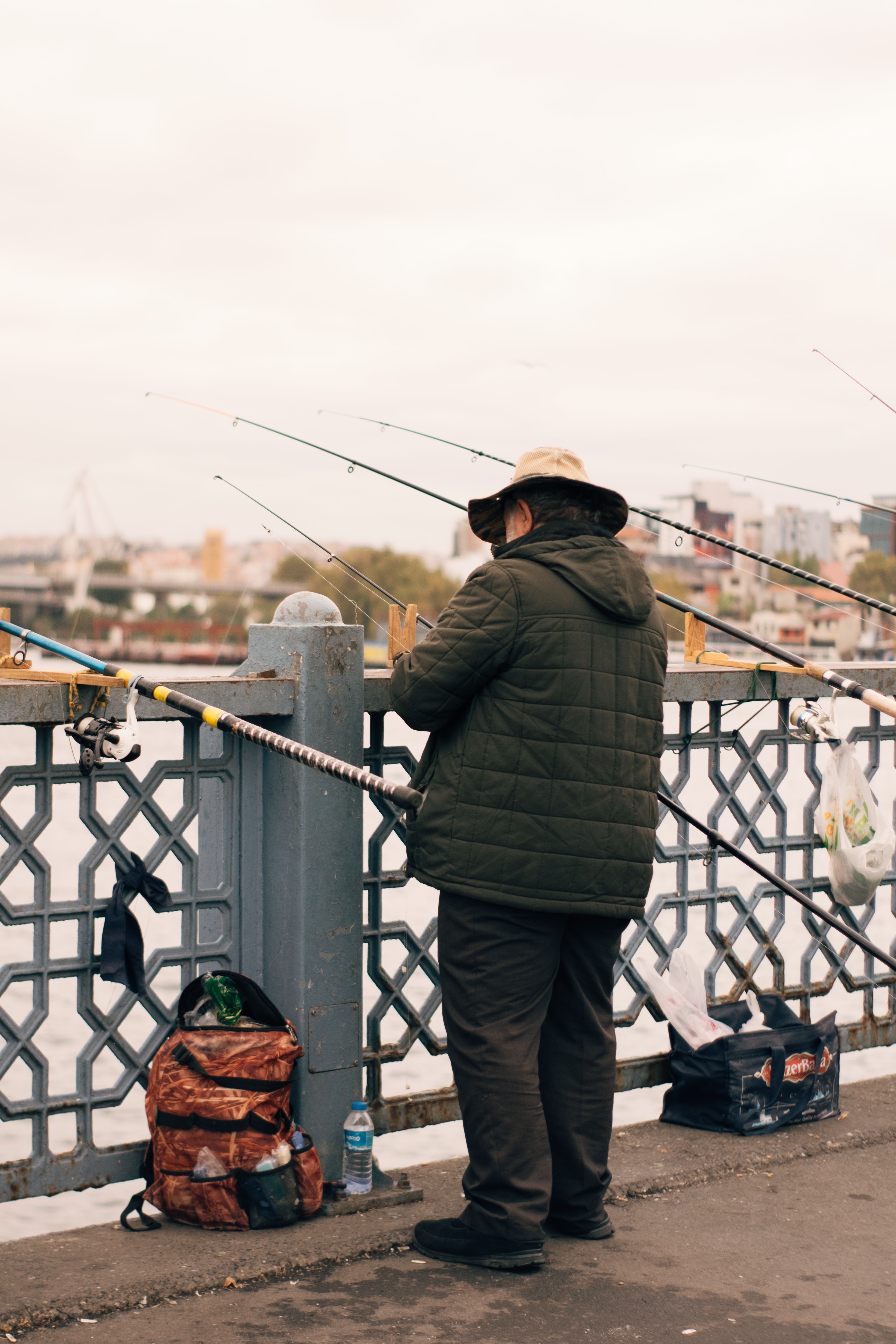 Man Fishing on Urban Bridge in Cool Weather · Free Stock Photo